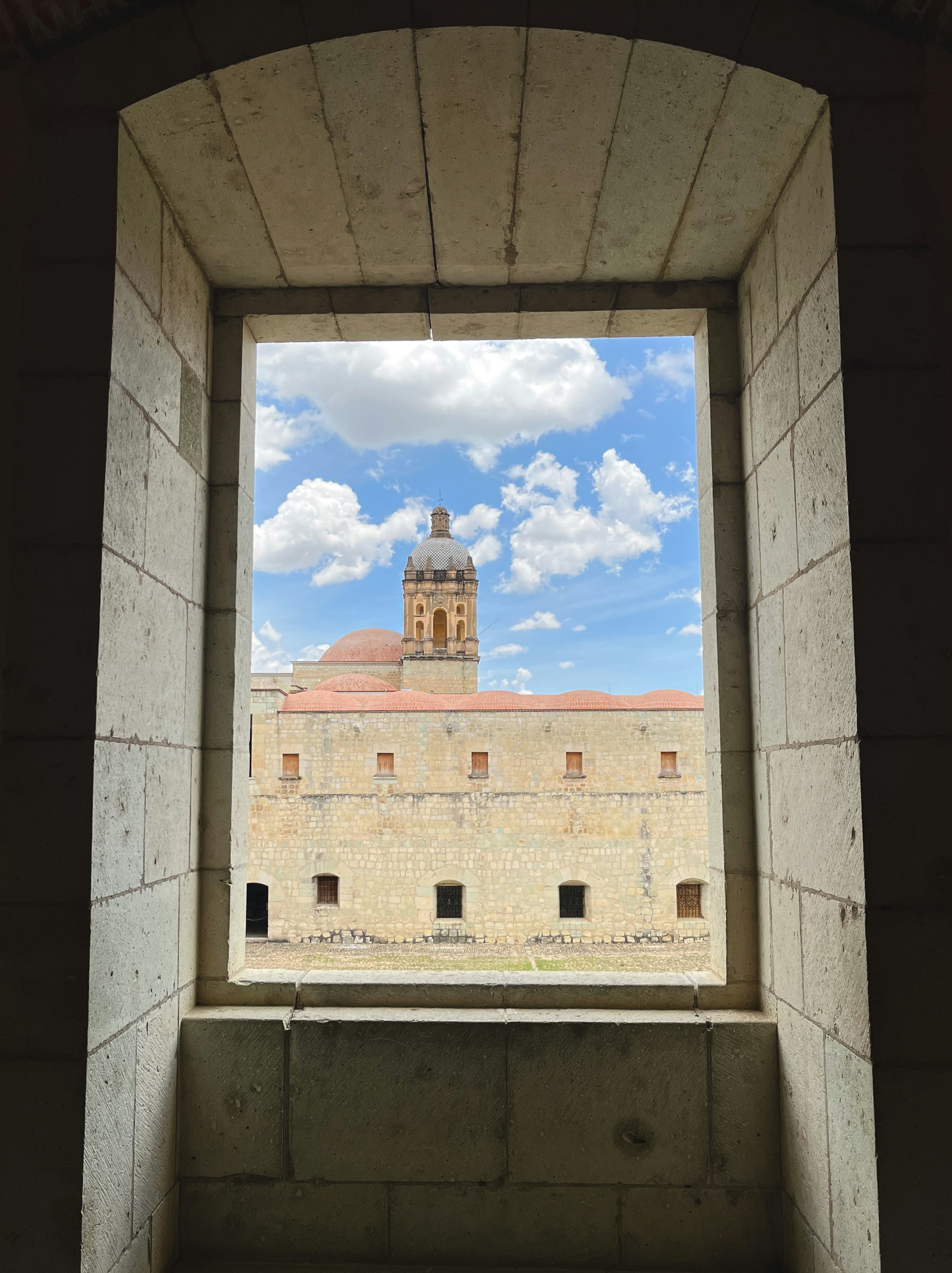 Courtyard View Through Stone Window: A Cathedral Tower Emerges