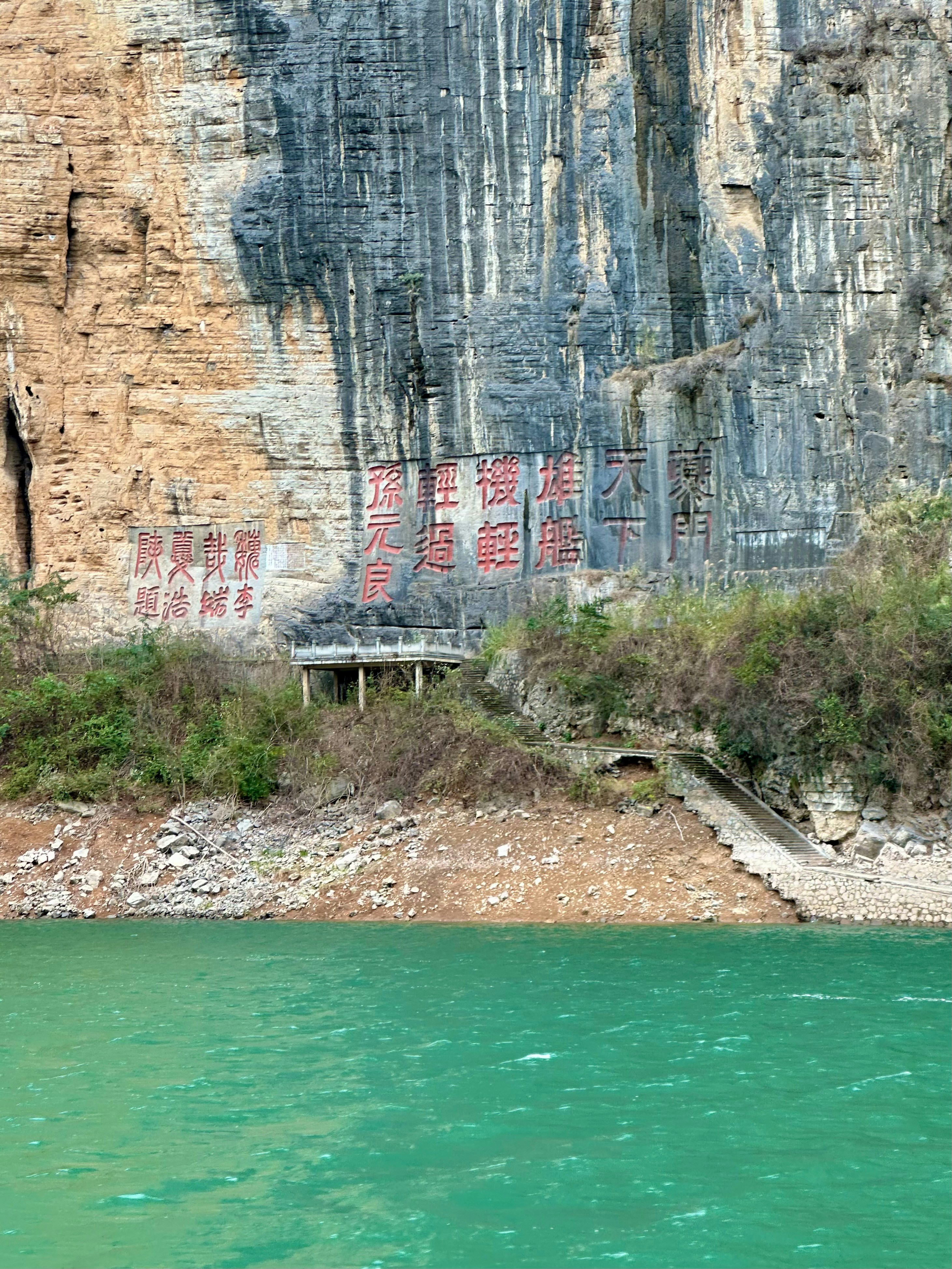 Red Chinese Characters on a Cliff Face Overlooking Turquoise Water