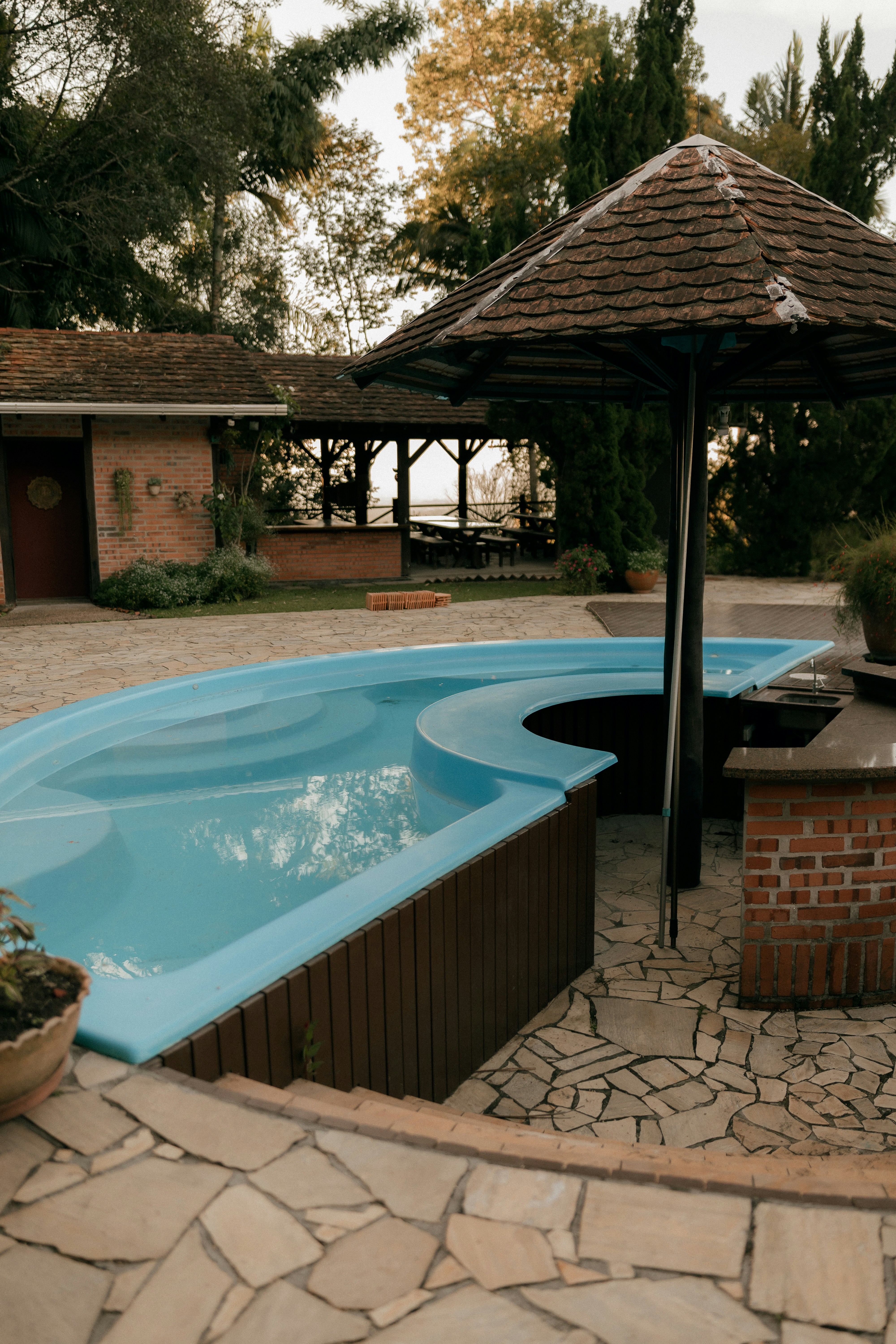 Curved turquoise pool under a rustic gazebo