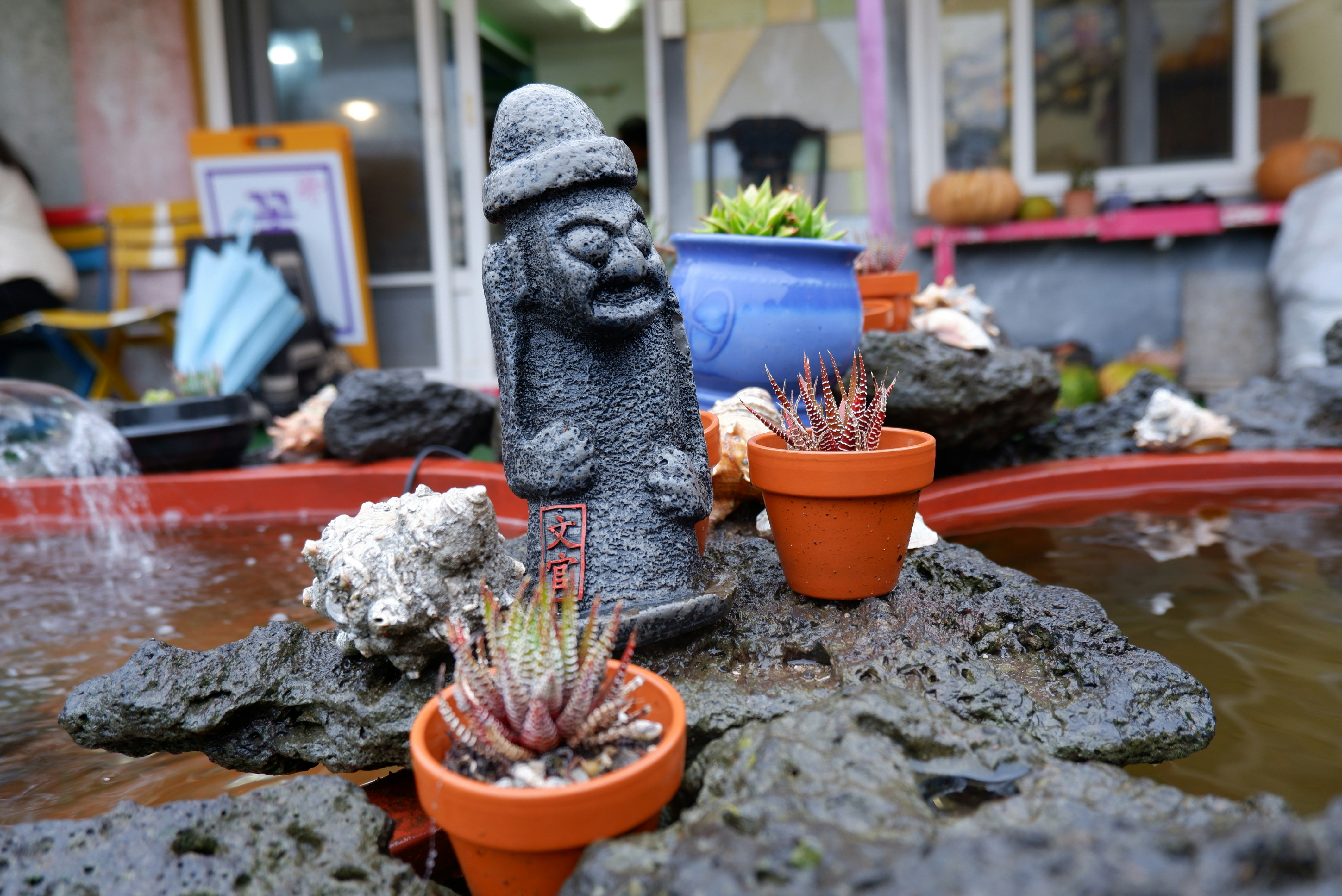 Miniature Sentinel by the Pond: A Pebbled Shrine with Succulents