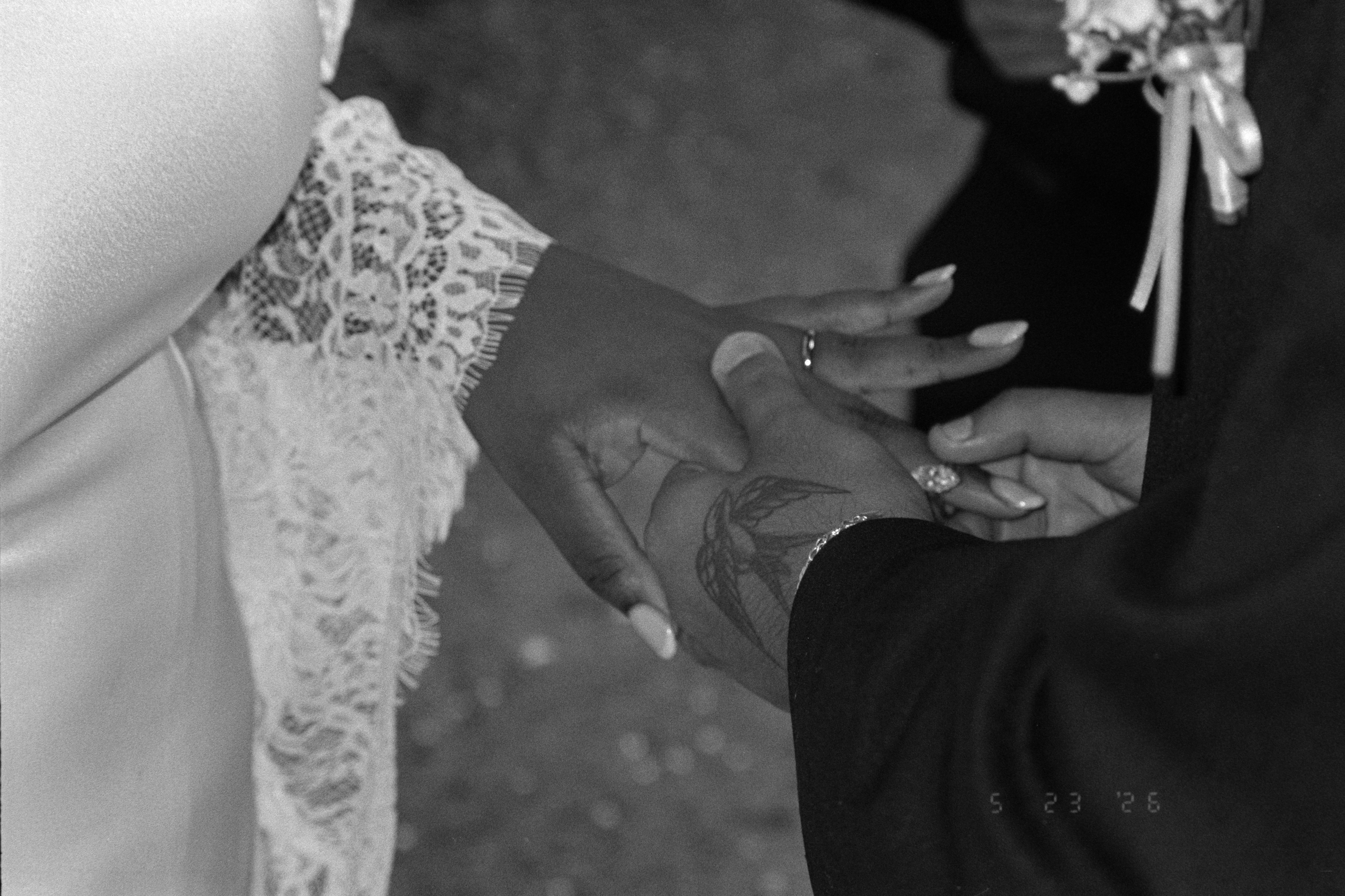 A hand placing a wedding ring on another's finger.