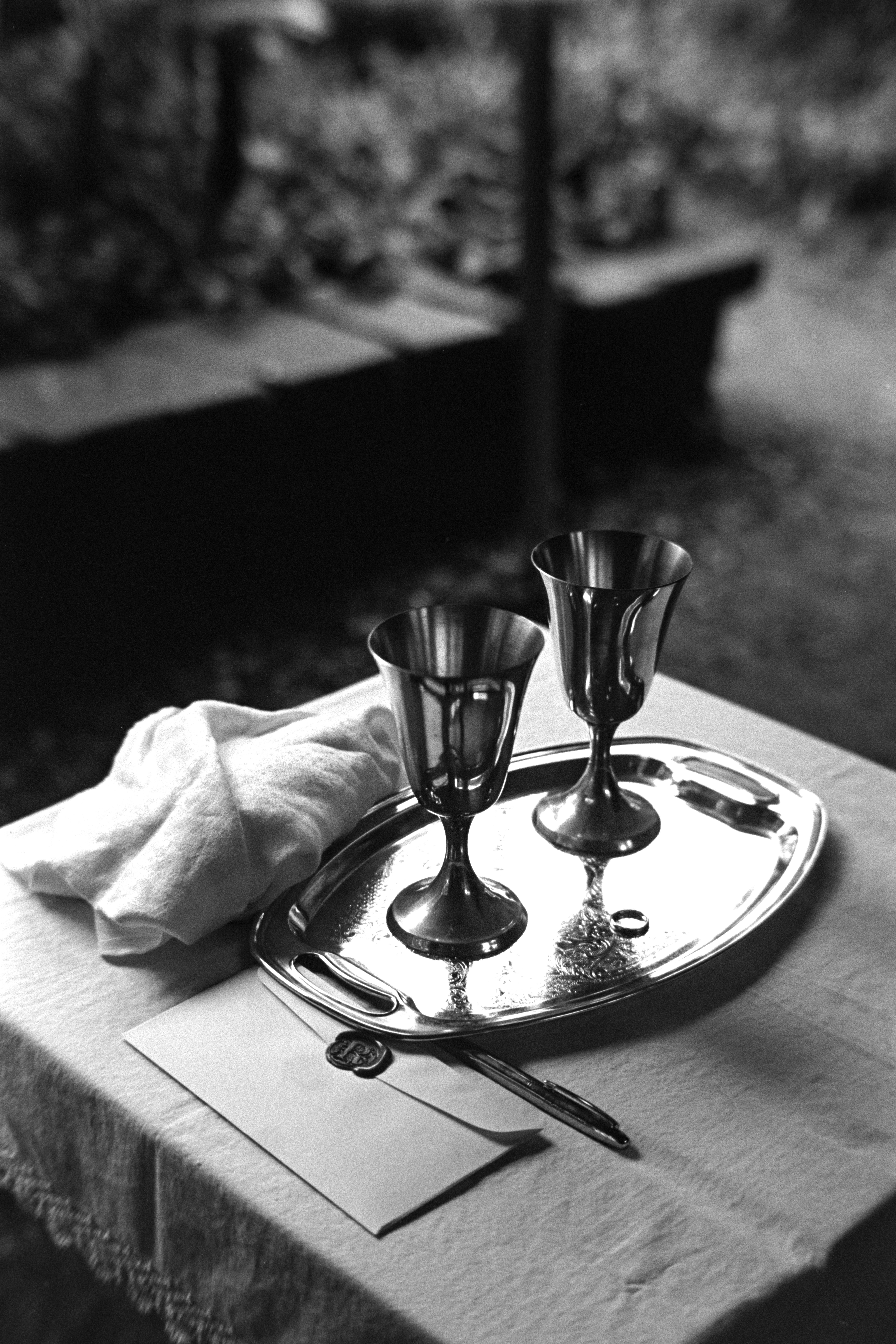 Two silver goblets, ring, and sealed envelope on a tray.