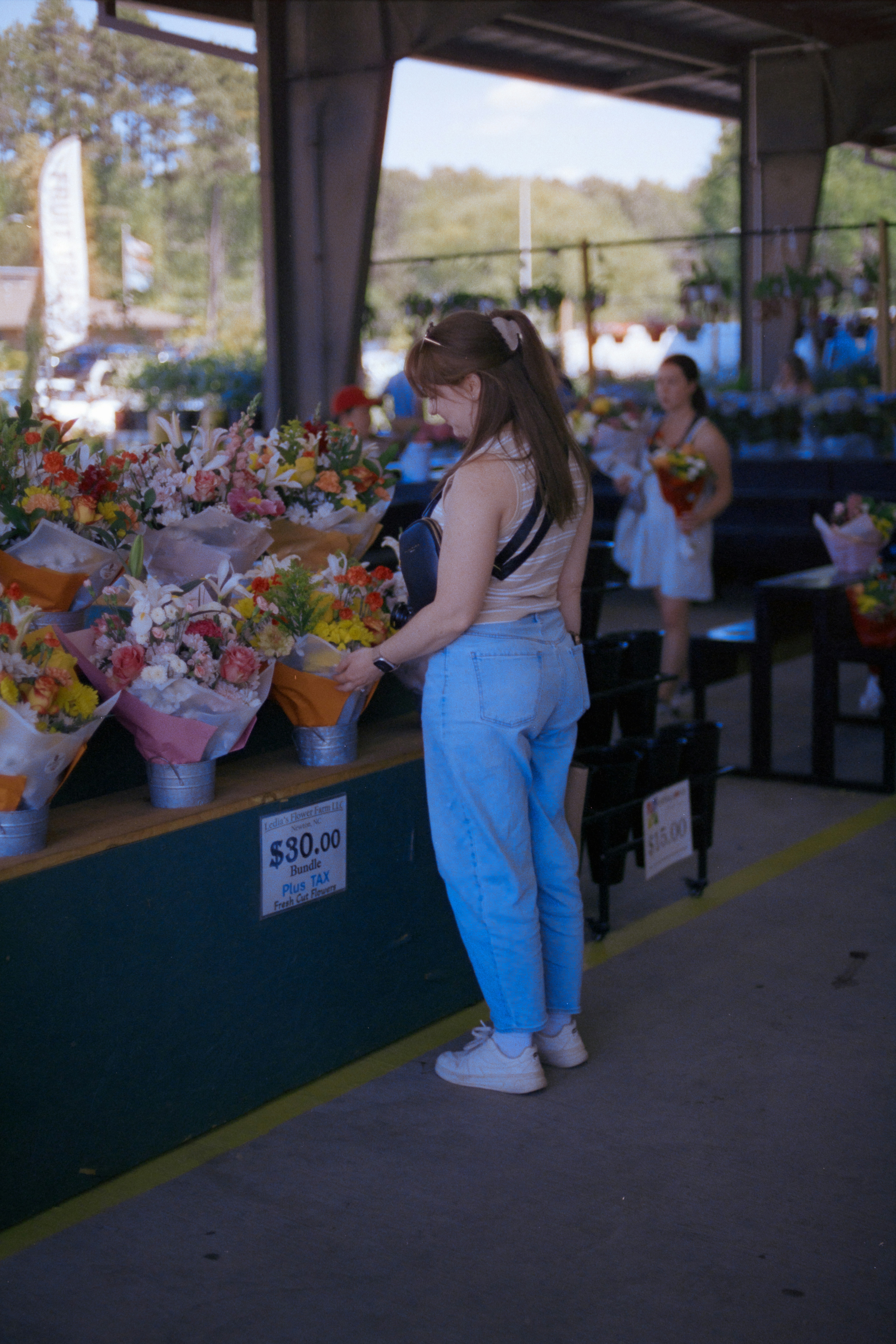 Market Flower Stand: A Young Shopper Amid Colorful Bouquets