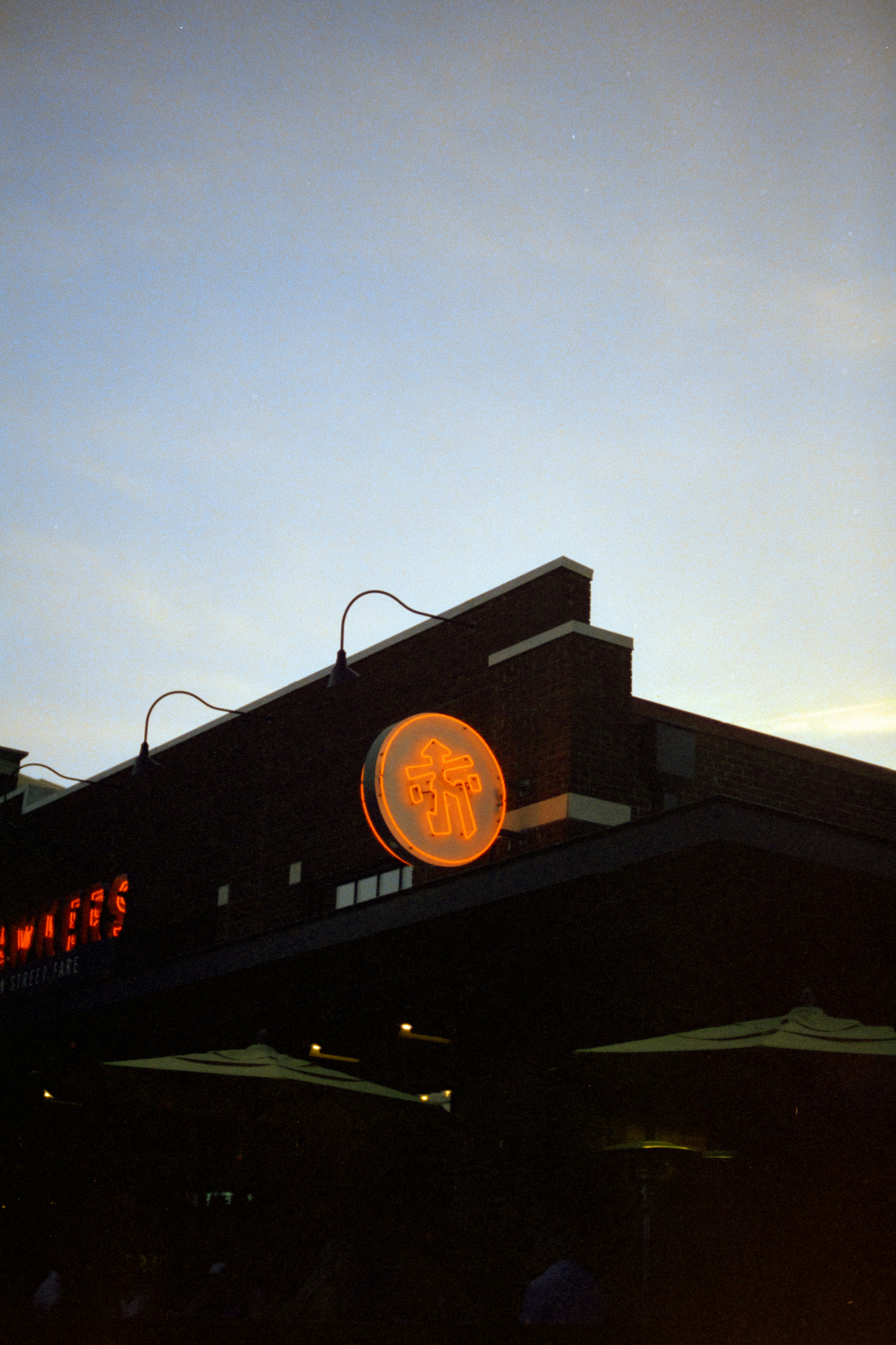 Neon Sign Over Brick Facade at Dusk