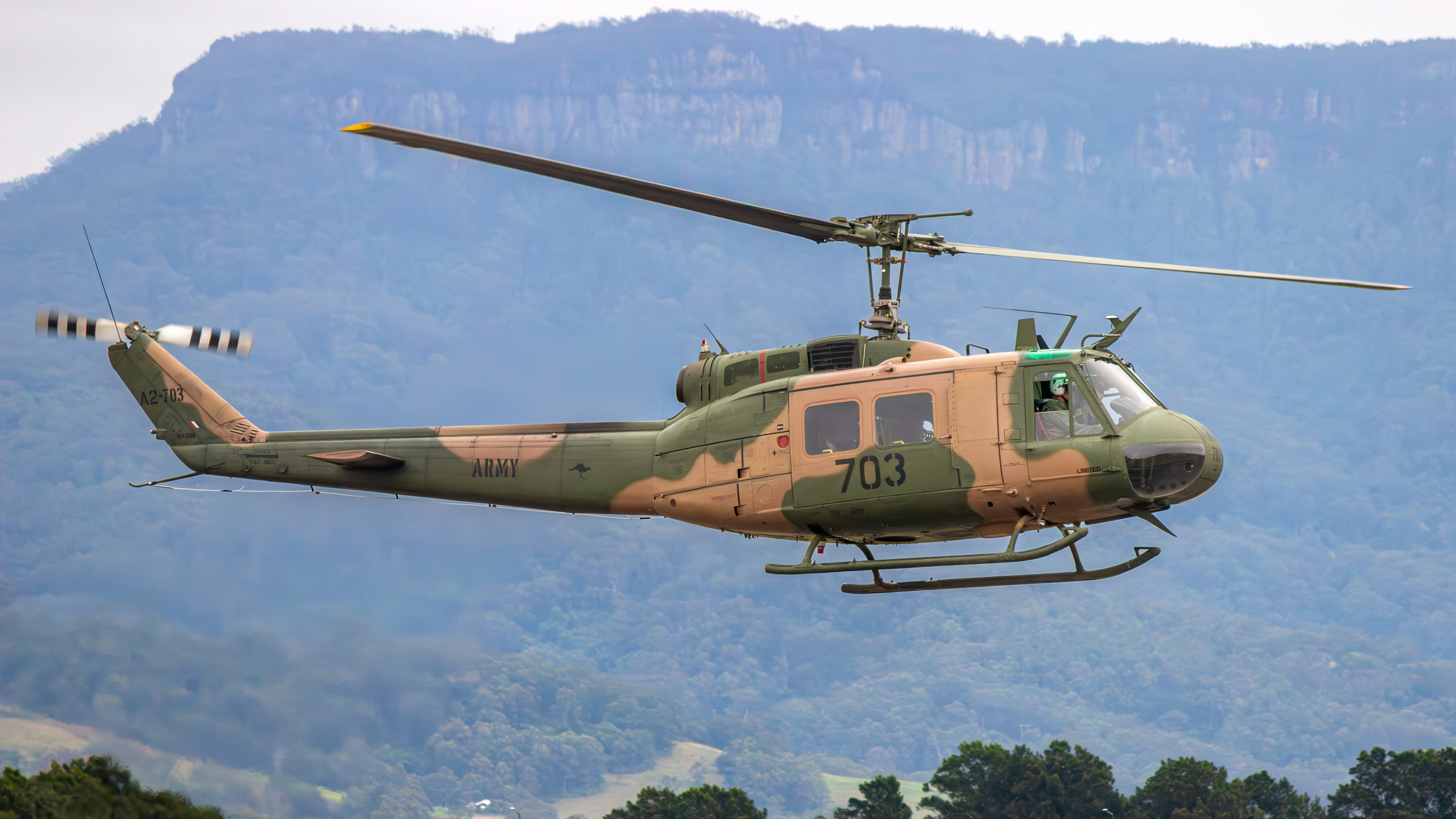 Camouflage in Flight: A UH-1 Huey Over the Valley