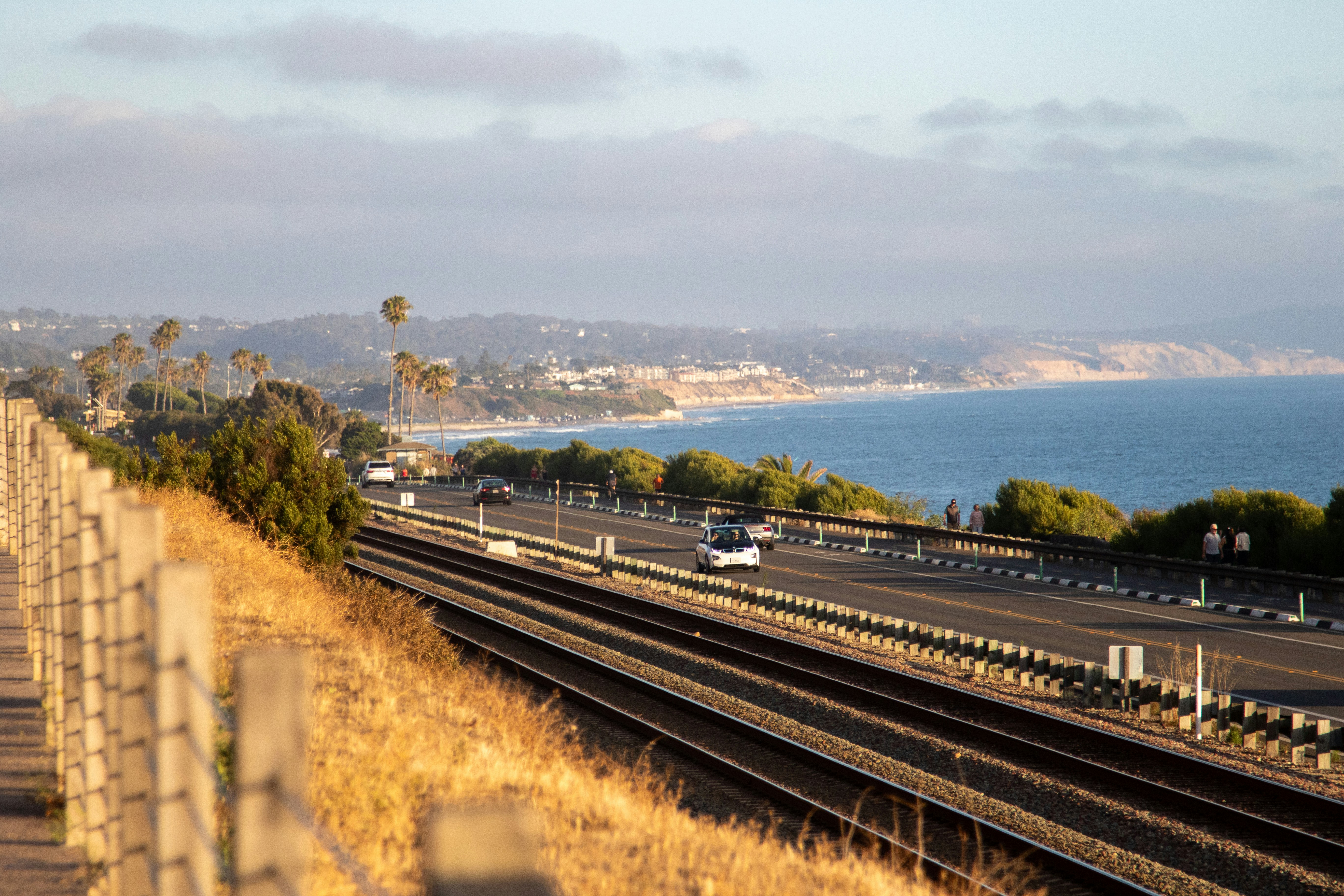 Tracks along the sunlit cliffside: a coastal road under calm skies