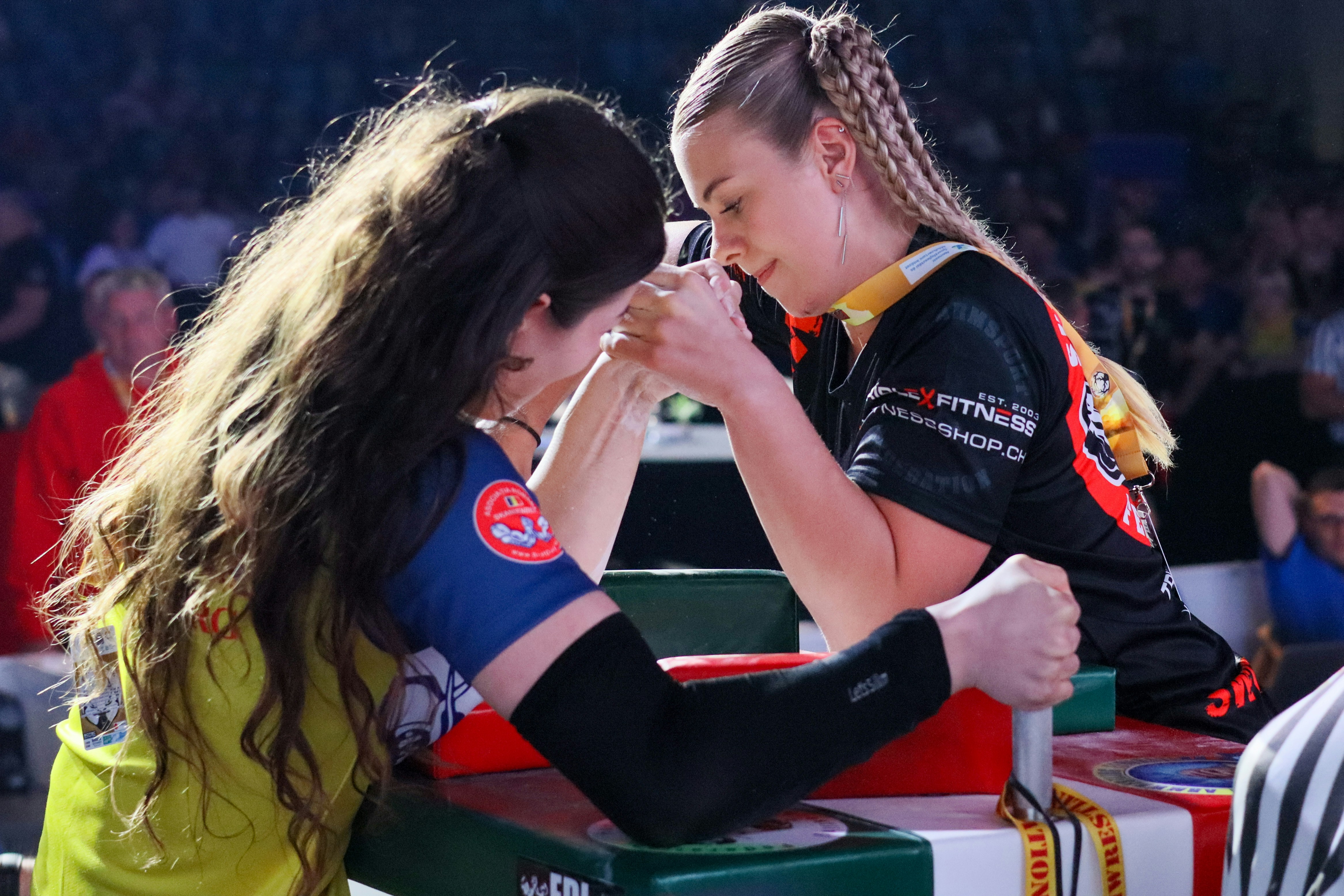 Two women arm wrestling with intense focus.