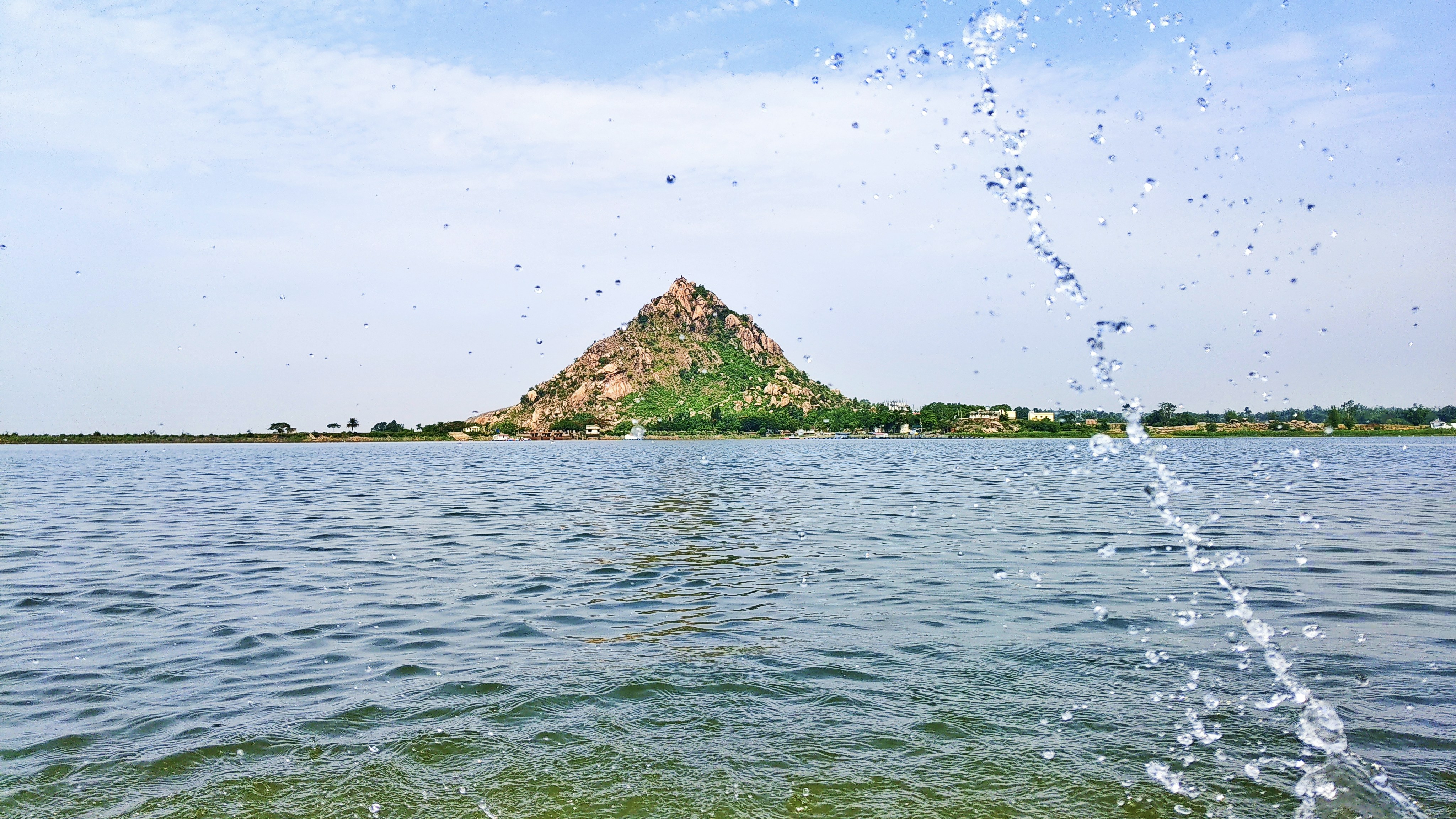 Isolated hill rising from a tranquil lake with a spray arc