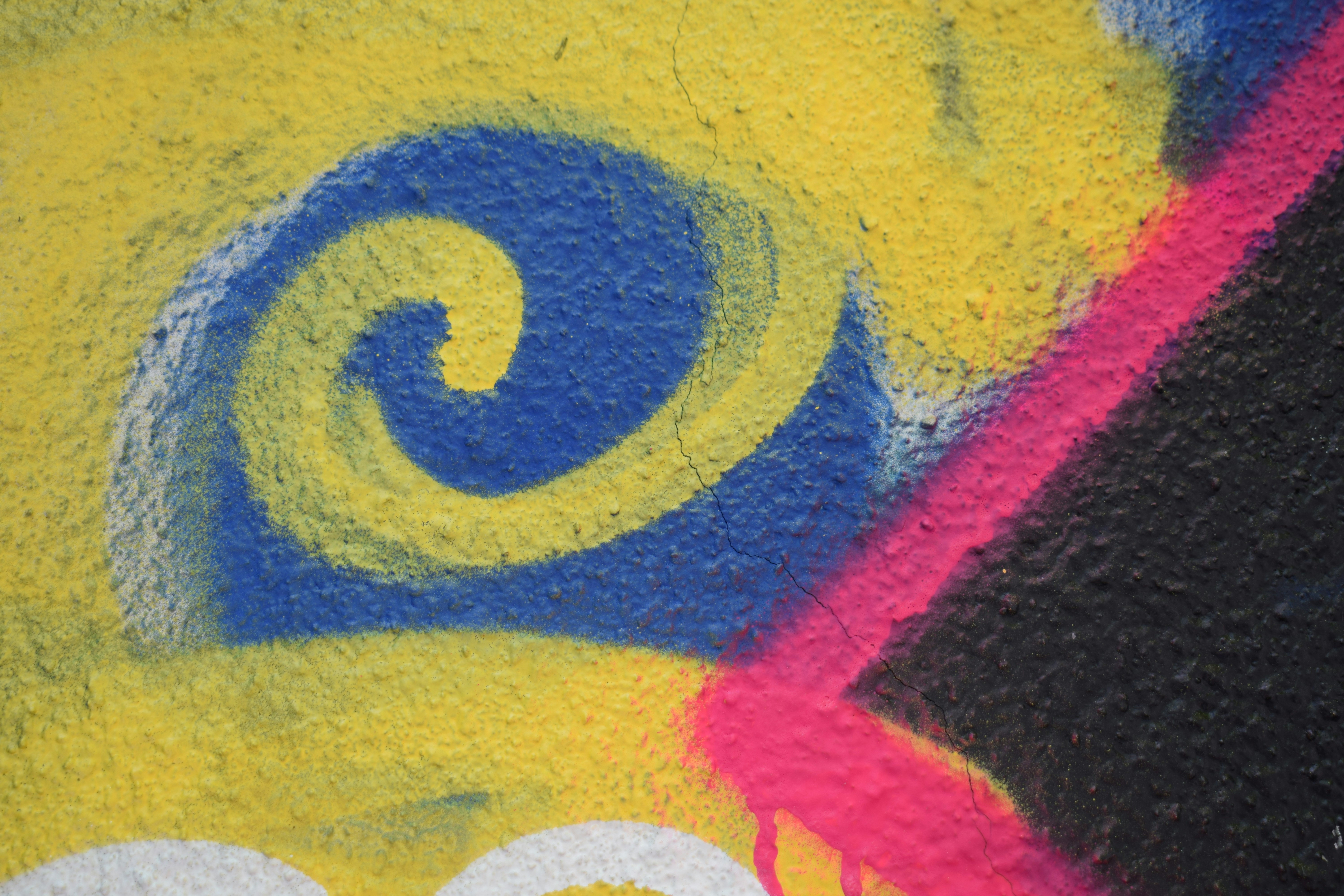 Vibrant Graffiti Spiral: Colorful Abstraction on a Crushed Wall