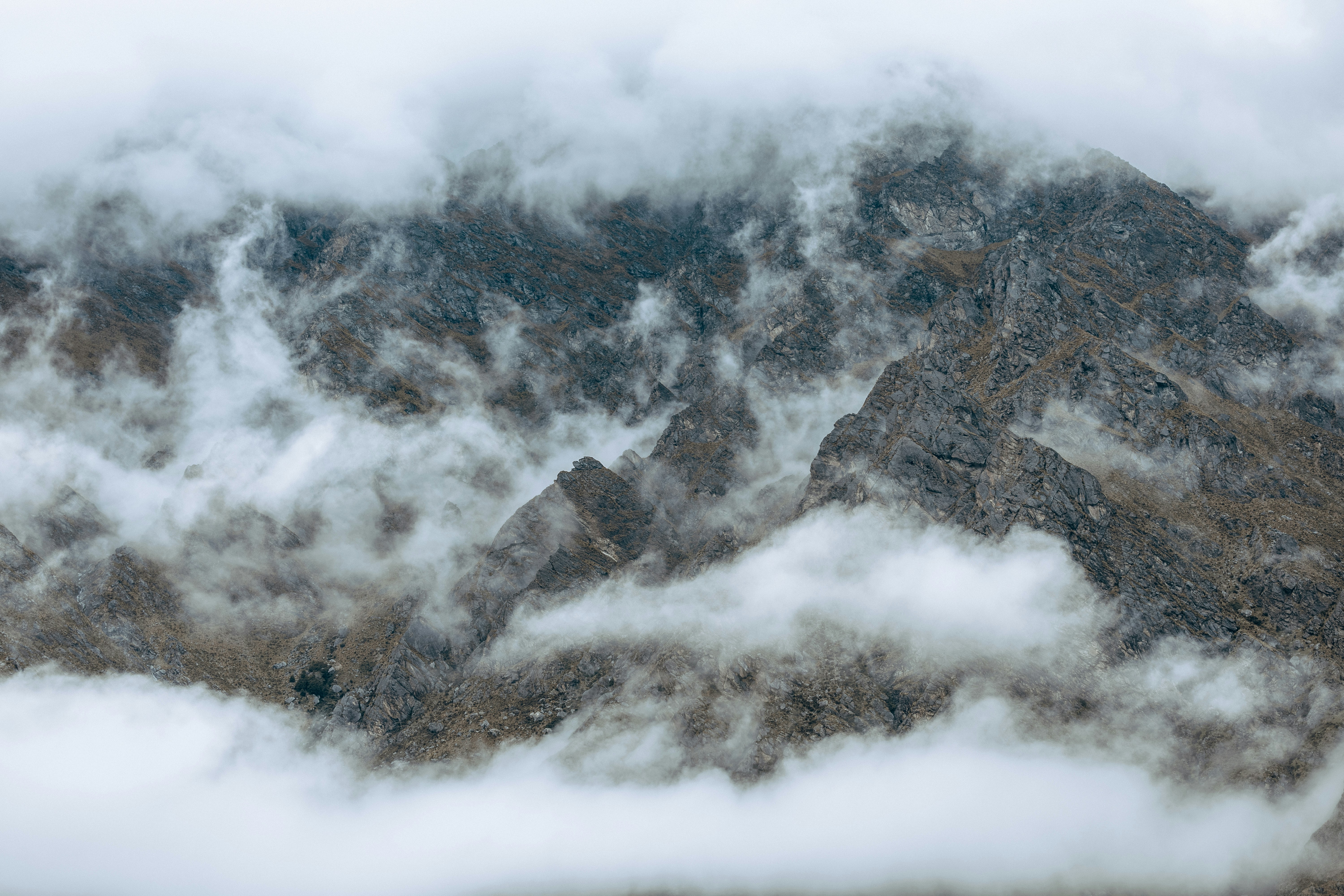 Rugged Peak Emerges Through a Veil of Clouds