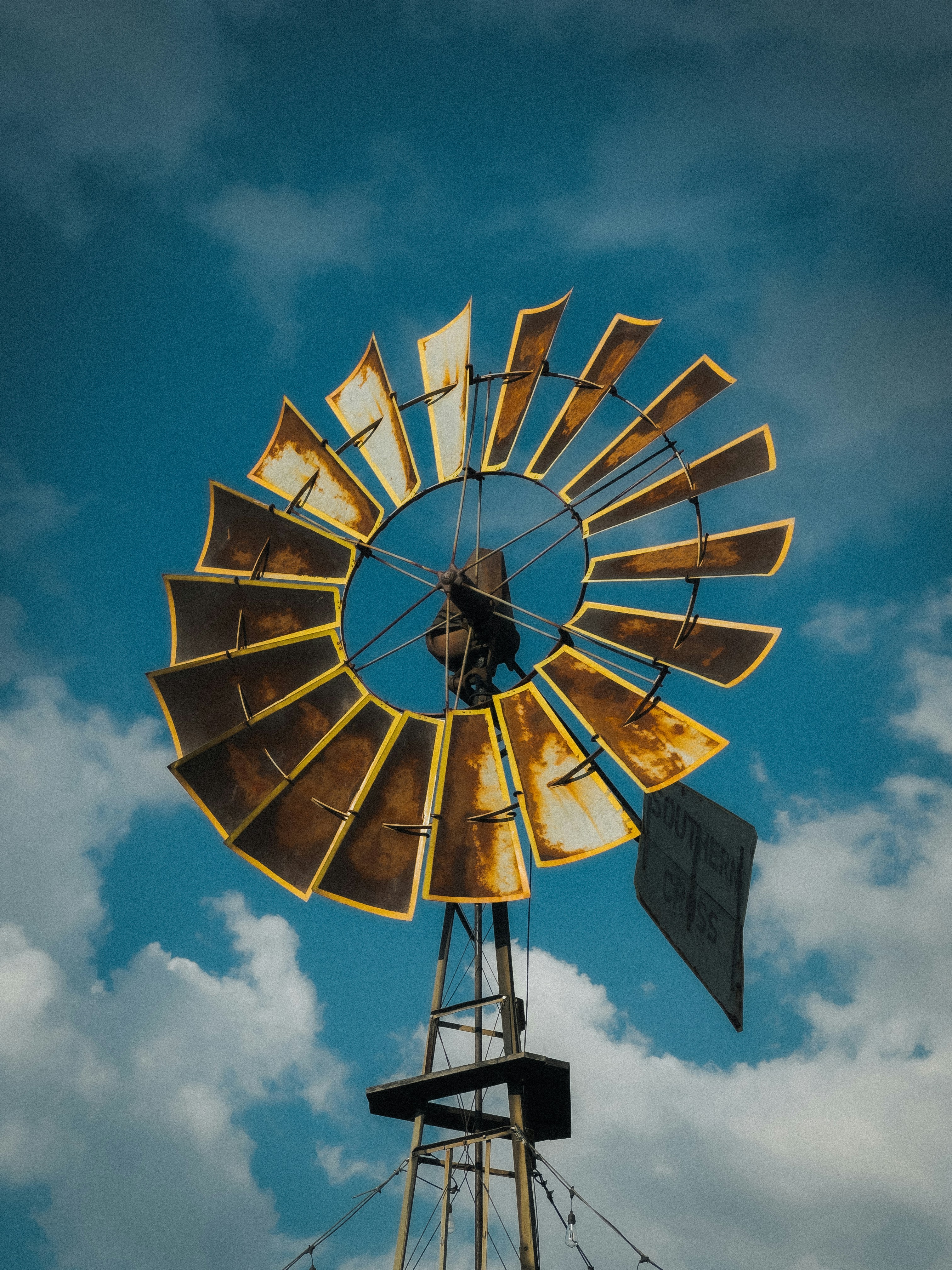 A rusty windmill stands against a blue sky.