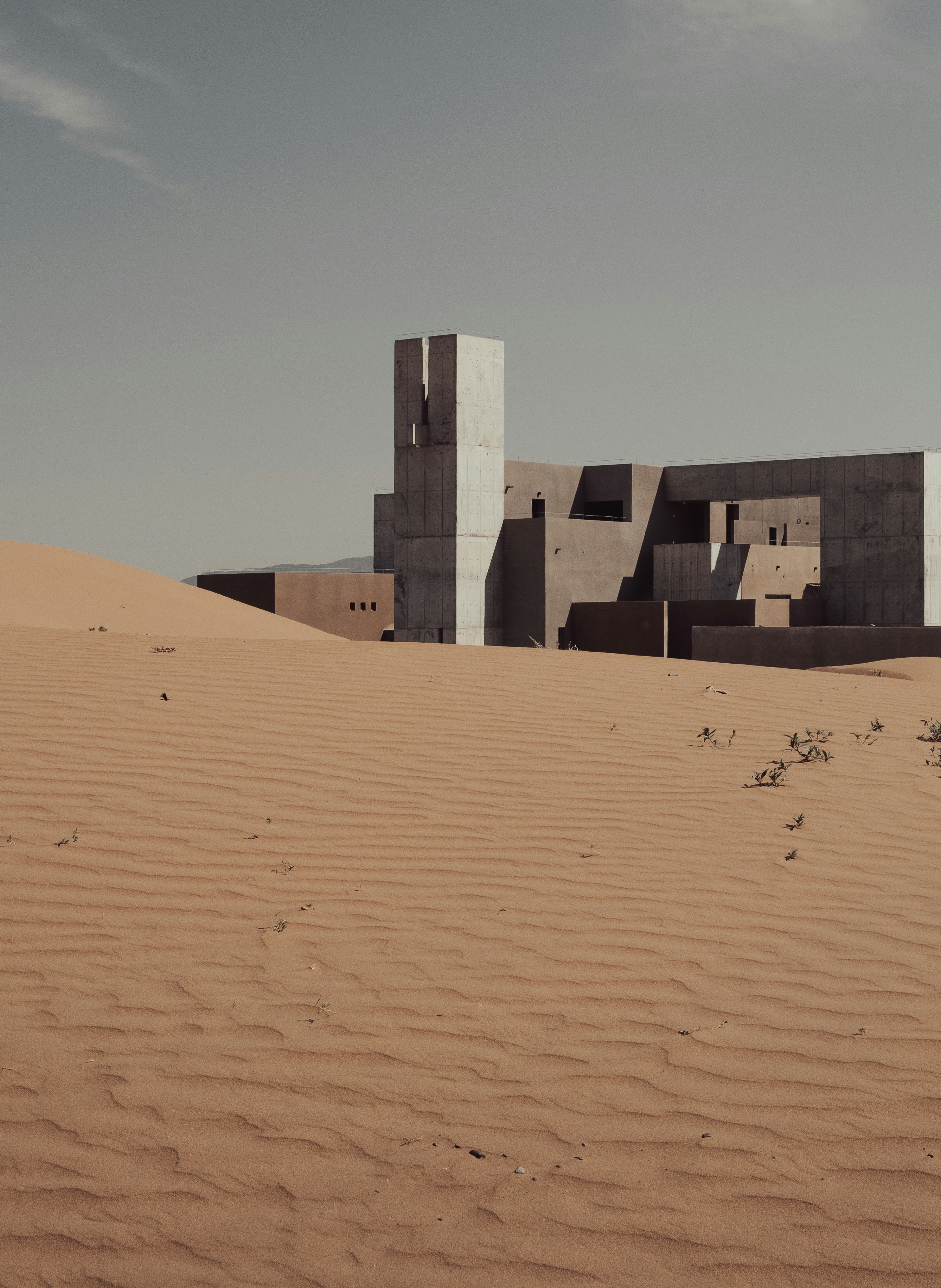 Desert Monolith: Concrete Structures Rising from Golden Dunes