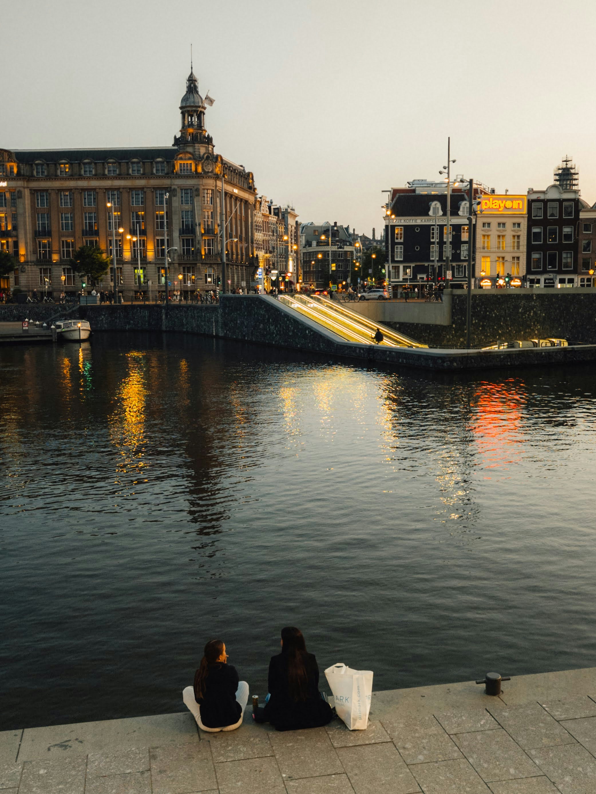 Evening by the Quiet Canal: Two Silhouettes and a Glowing Bridge