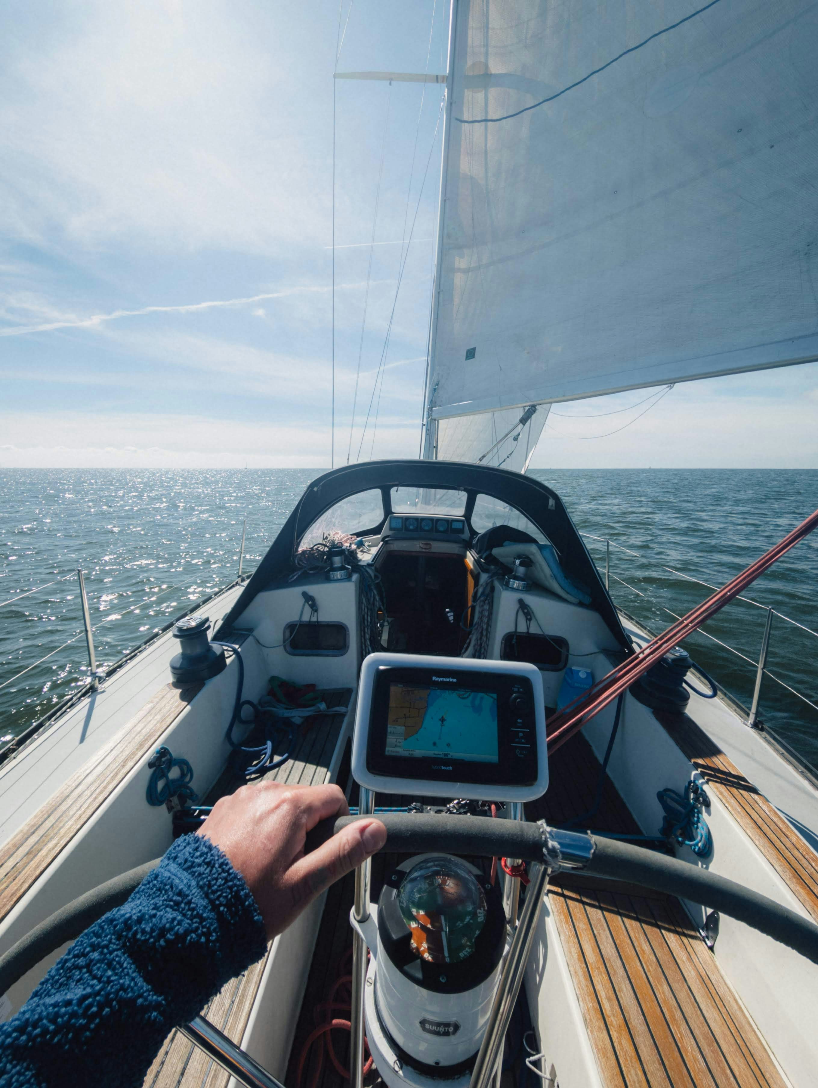 Hand on the helm of a sailboat at sea.