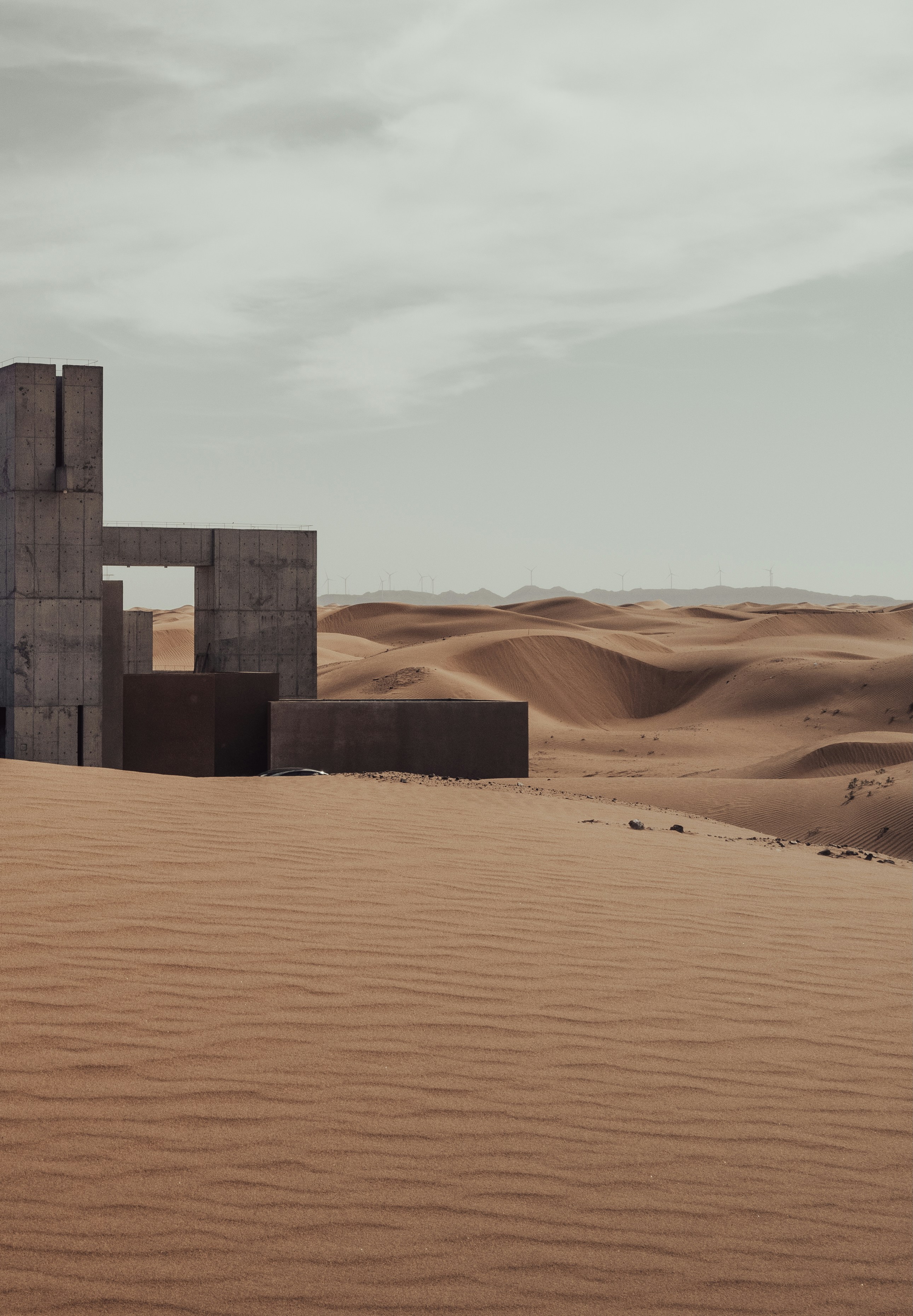 Concrete structures in a desert of rolling sand dunes.