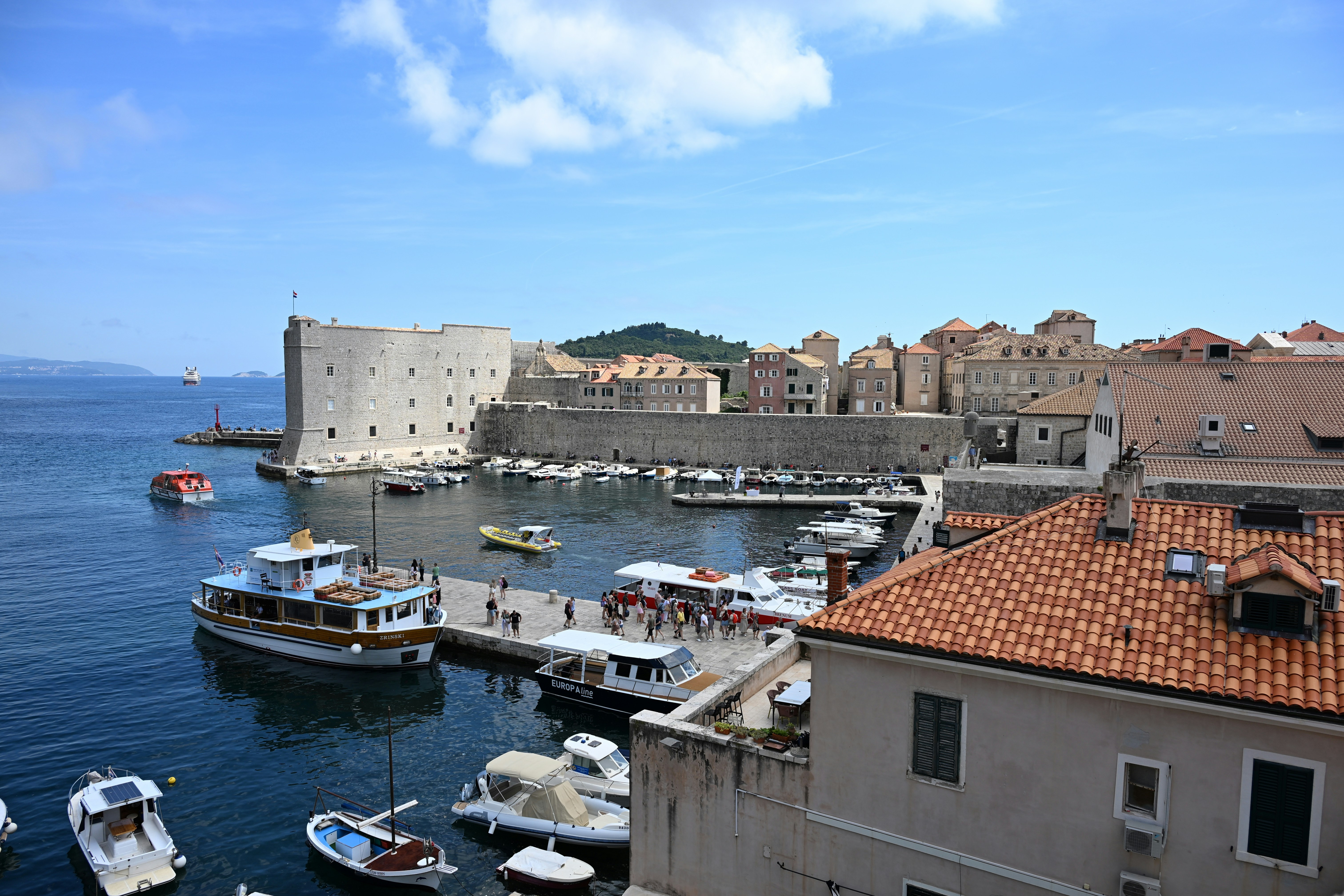 Boats gather in Dubrovnik's historic Old Port beneath centuries-old stone fortifications, where the Adriatic Sea meets one of Croatia's most iconic coastal cities.