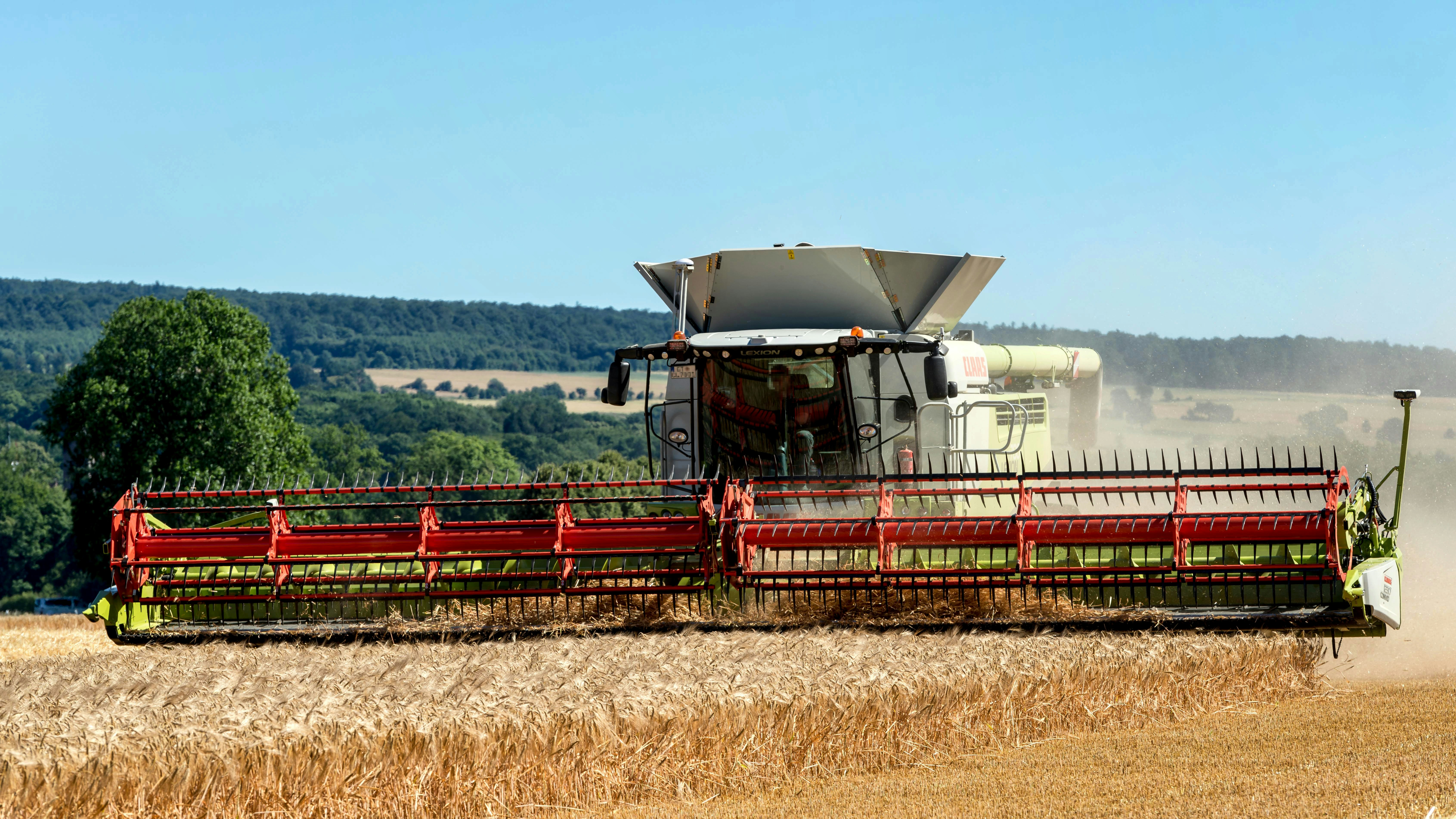 Harvest Horizon: Red Combine Across Golden Wheat Field