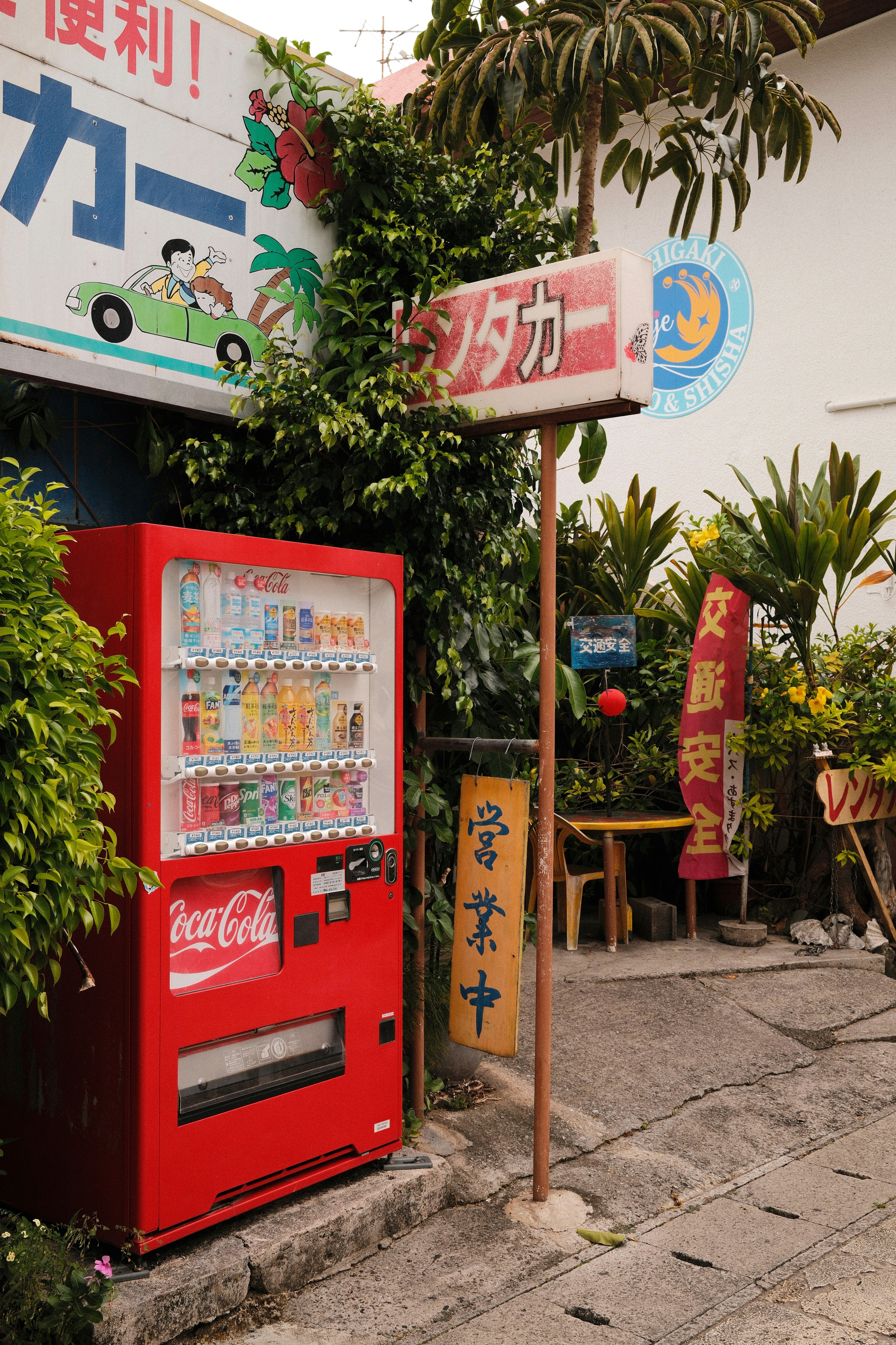 Vibrant Street Vending: A Red Coca‑Cola Vending Machine Among Tropical Foliage