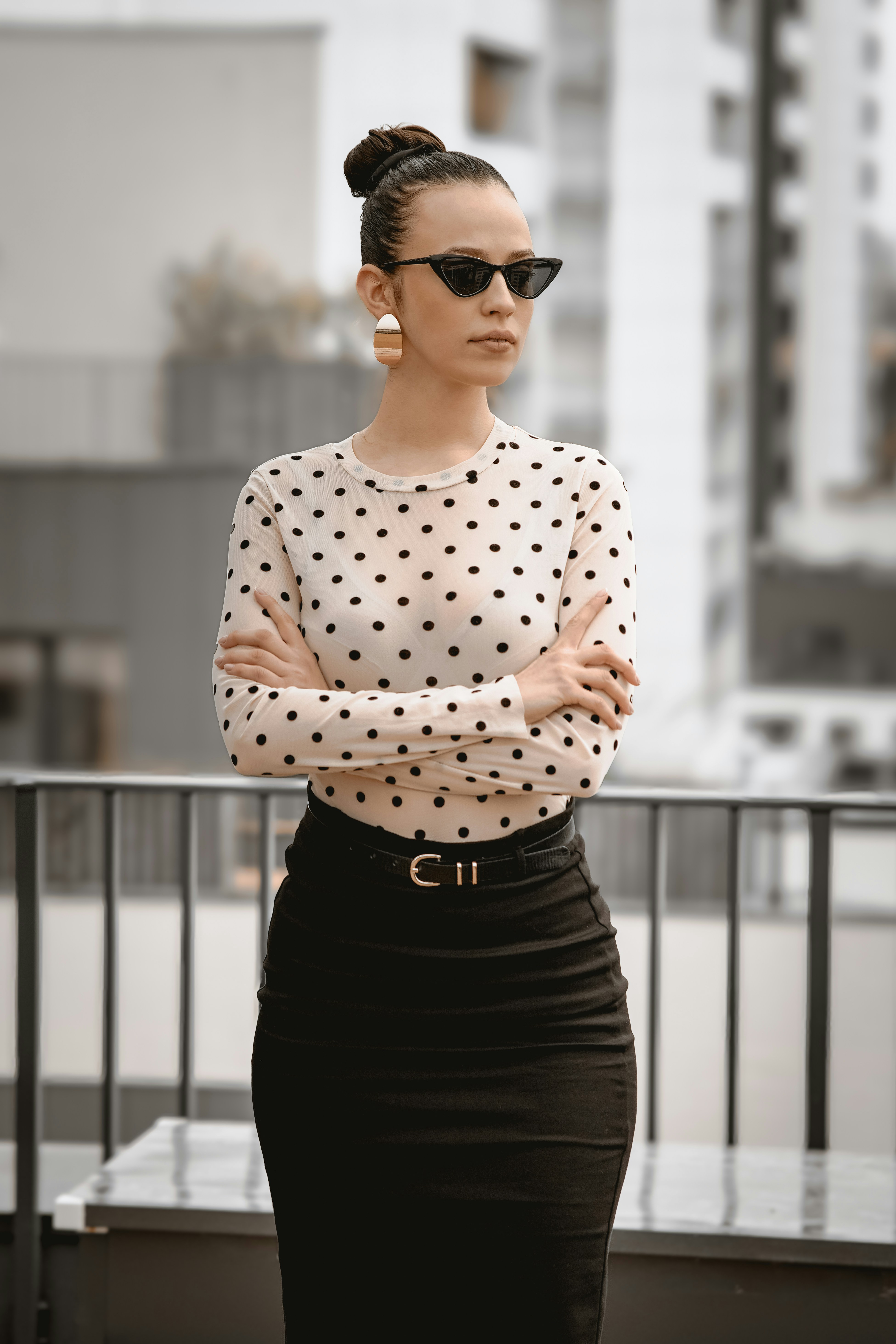Stylish woman with crossed arms wearing sunglasses and polka dots.