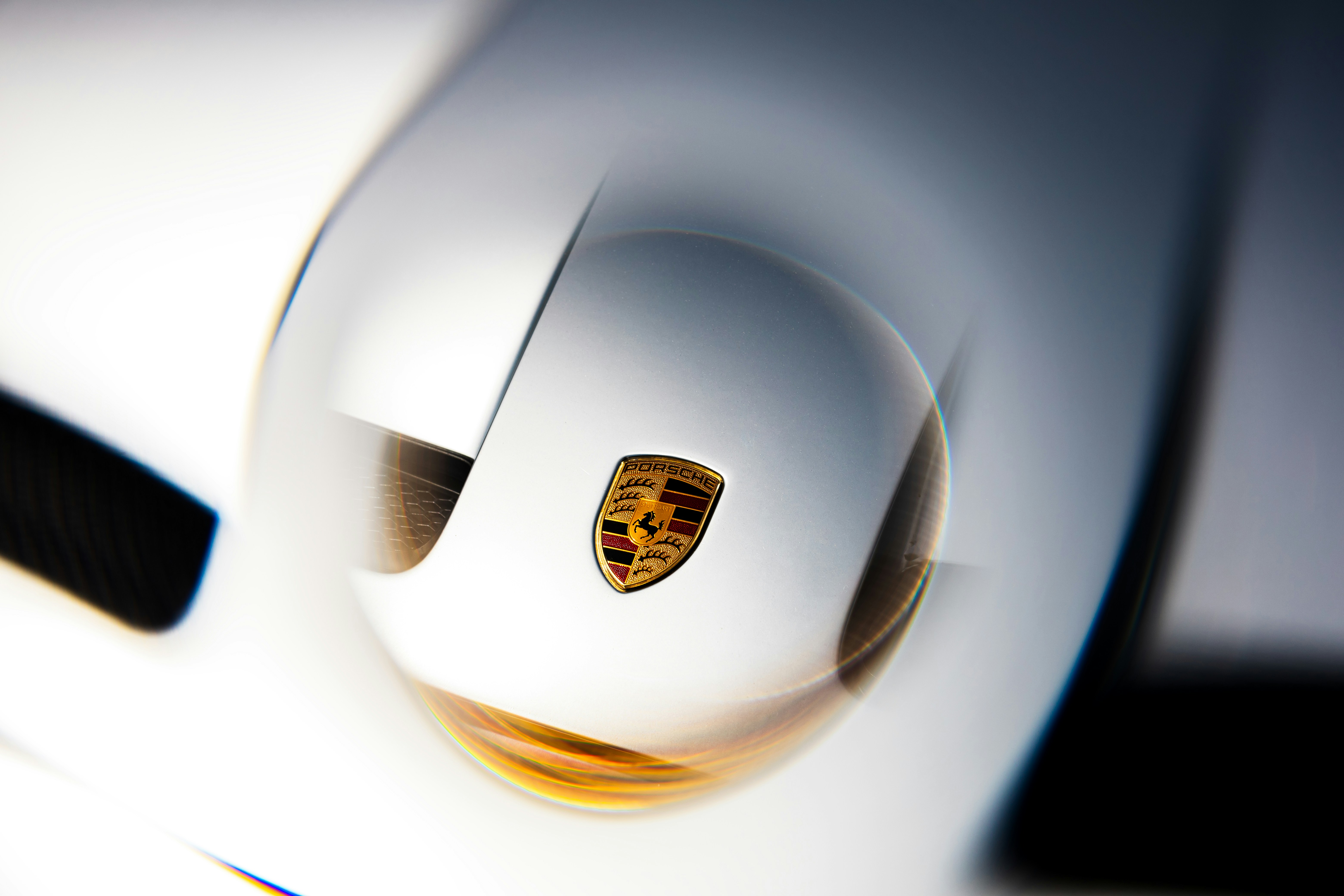 Focused Emblem: Porsche Badge Reflections in a Curved Hood Highlight