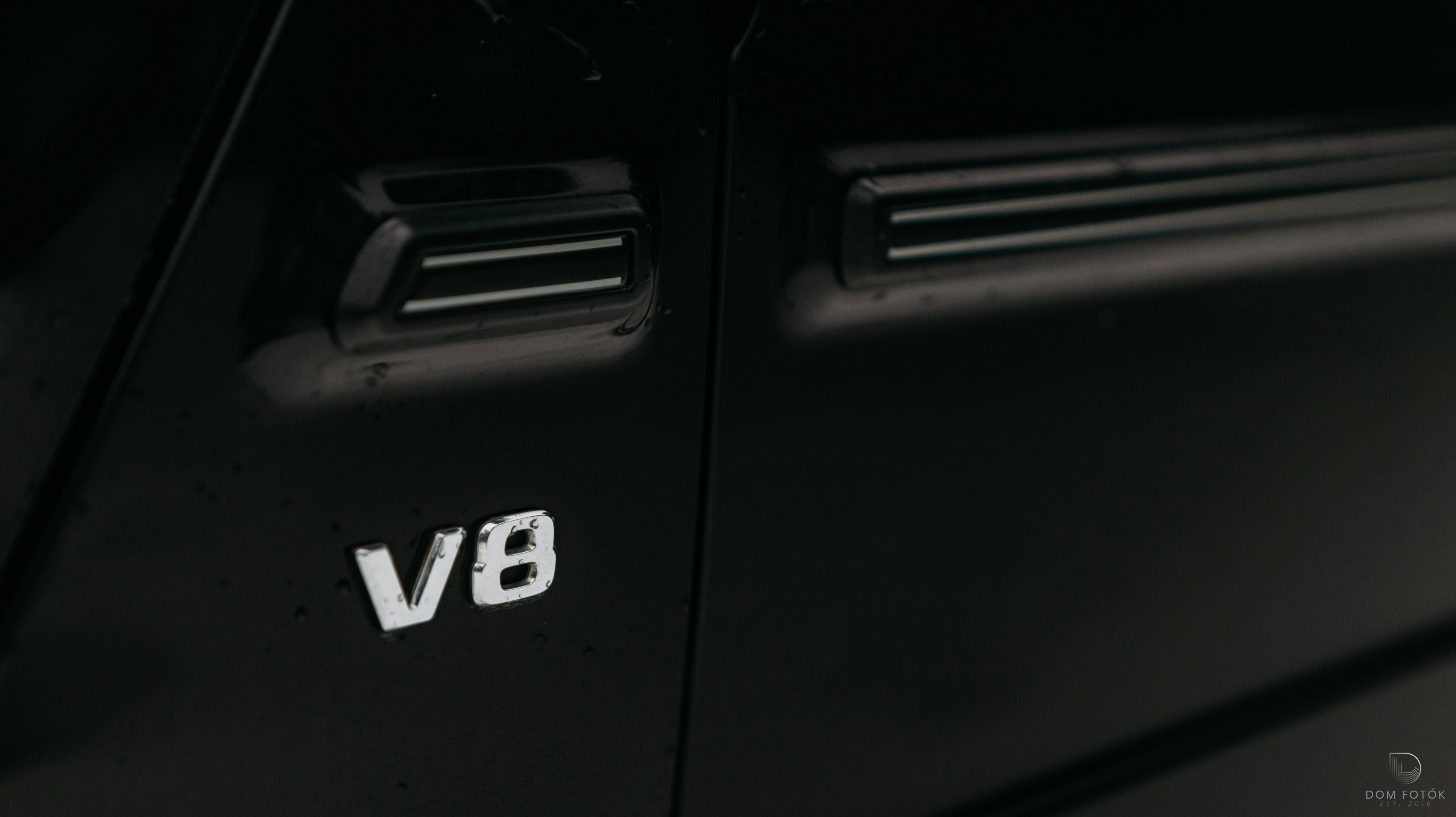 Metallic V8 Emblem on a Matte Dark Vehicle