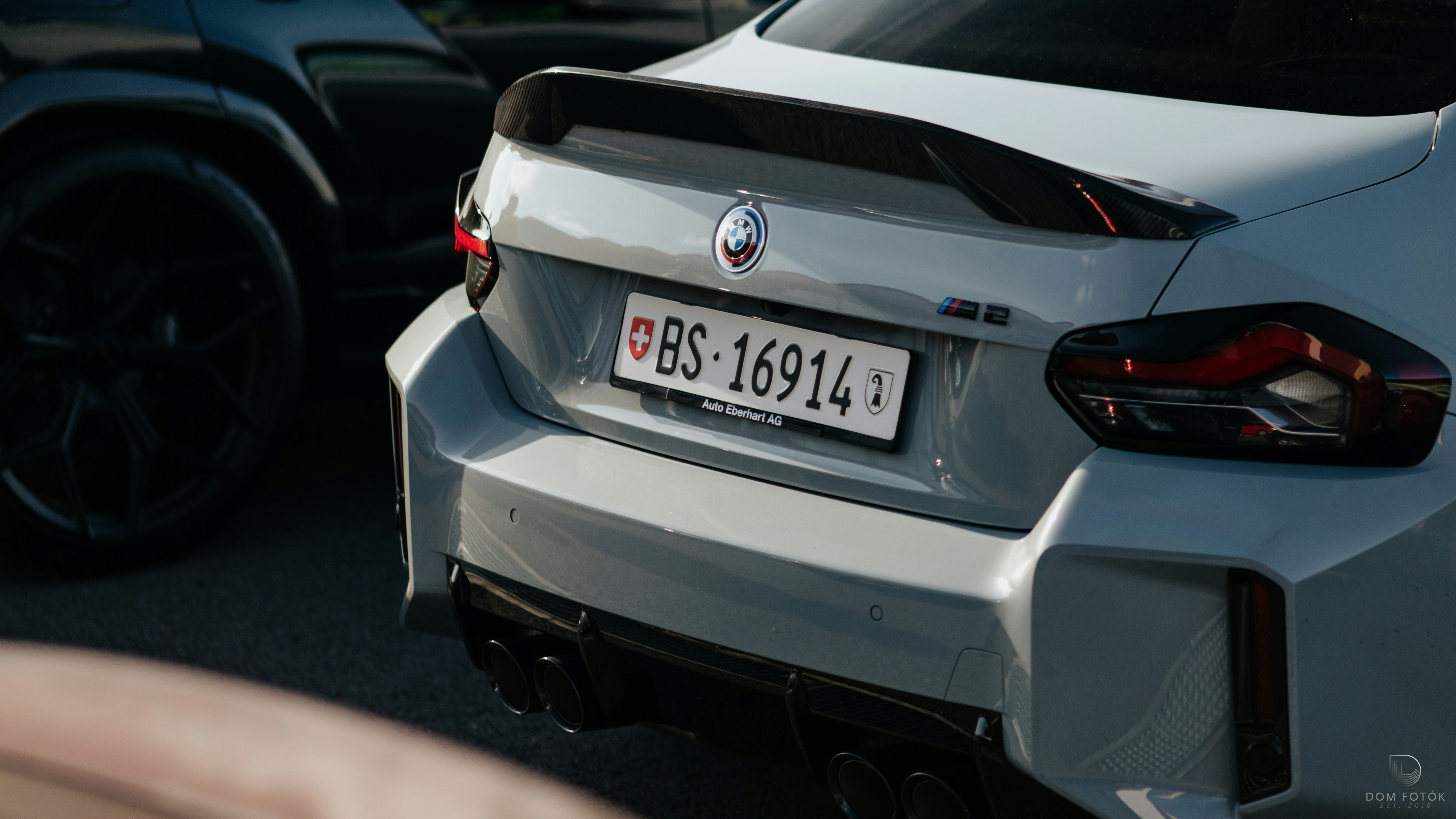 Rear View of a Modded White BMW-Look Sedan with Swiss Plate at Dusk Event