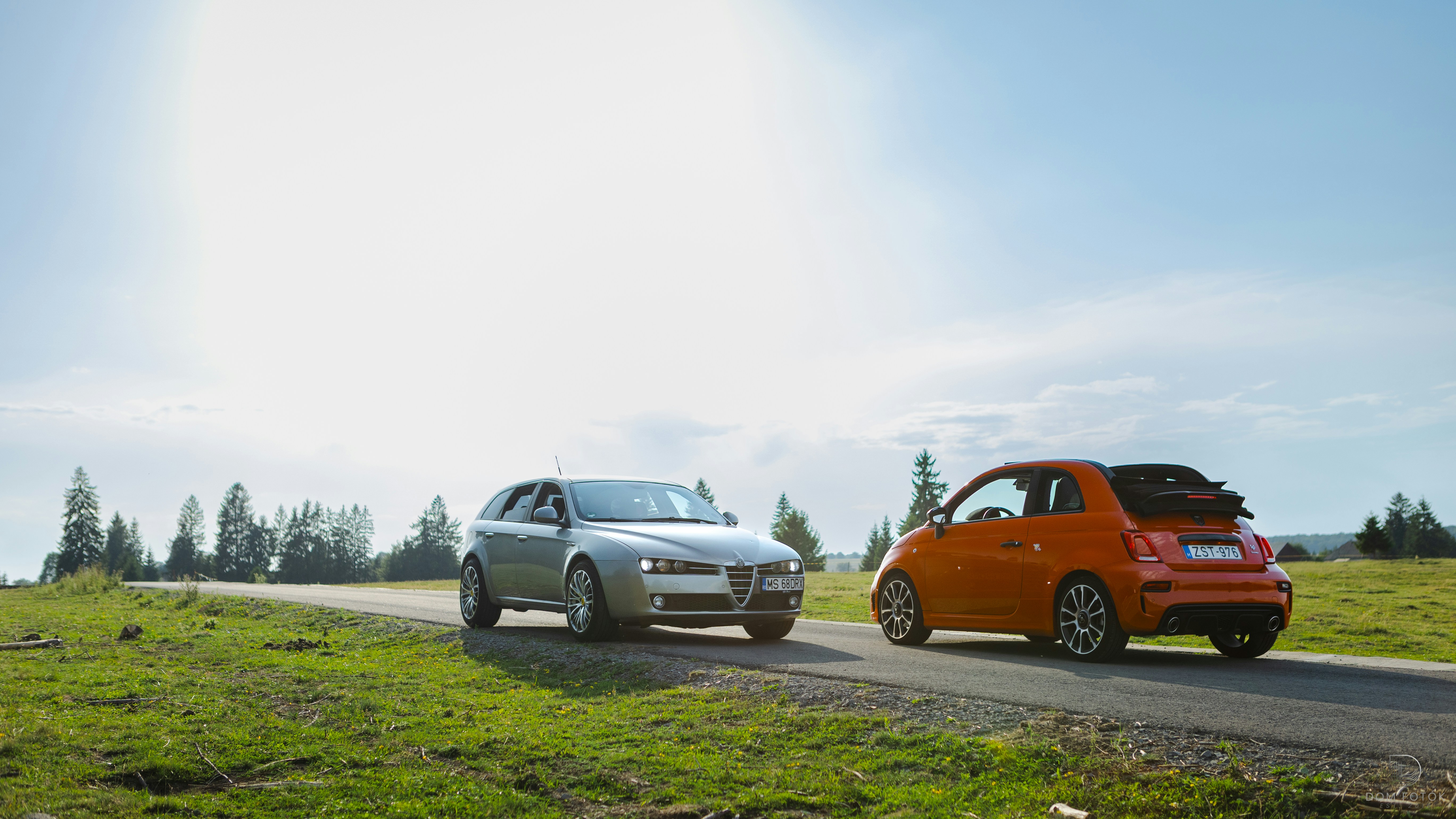 Two SUVs on a sunlit country road