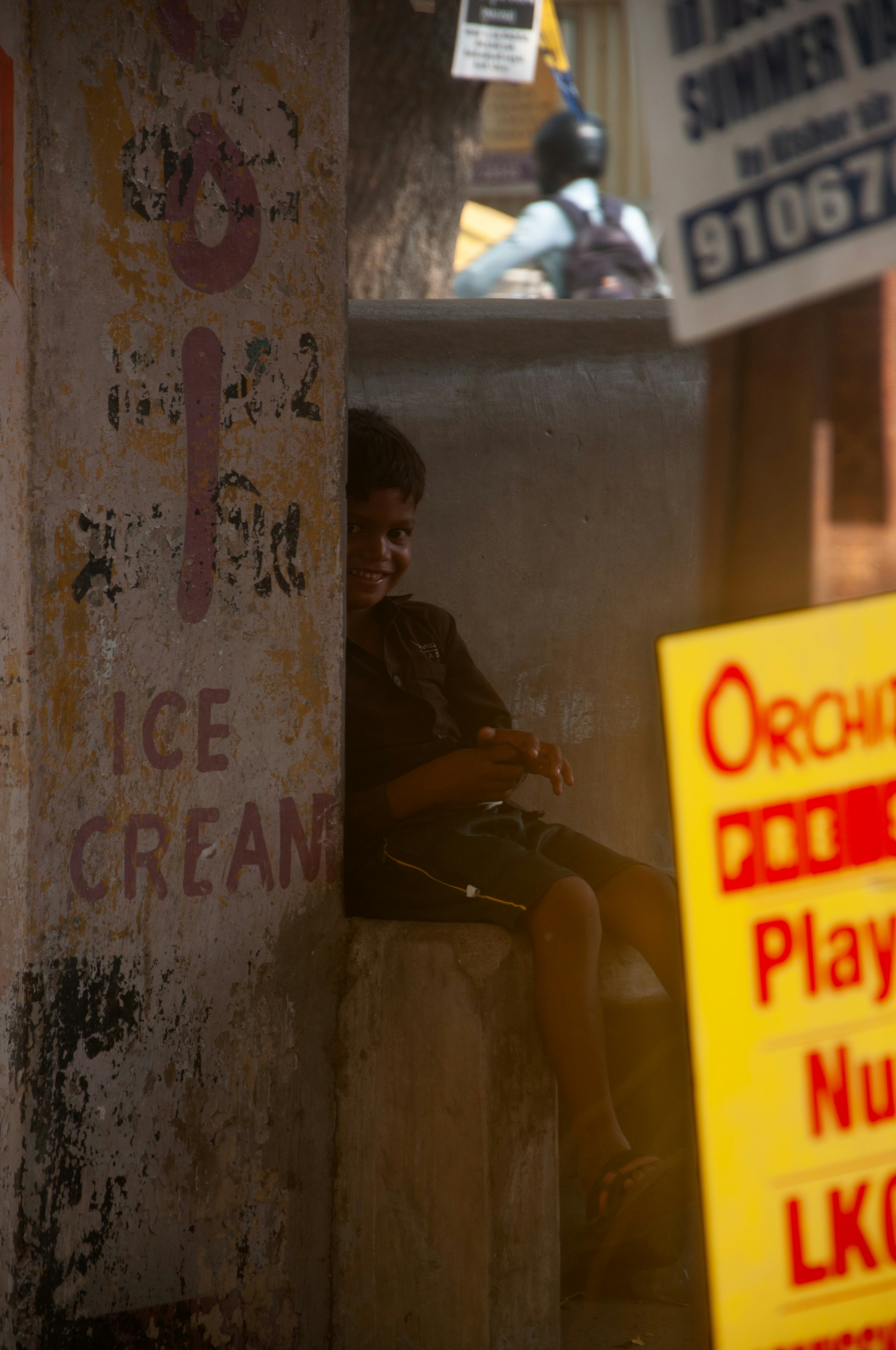 Child in the Shadow: A Quiet Moment by the Ice Cream Wall