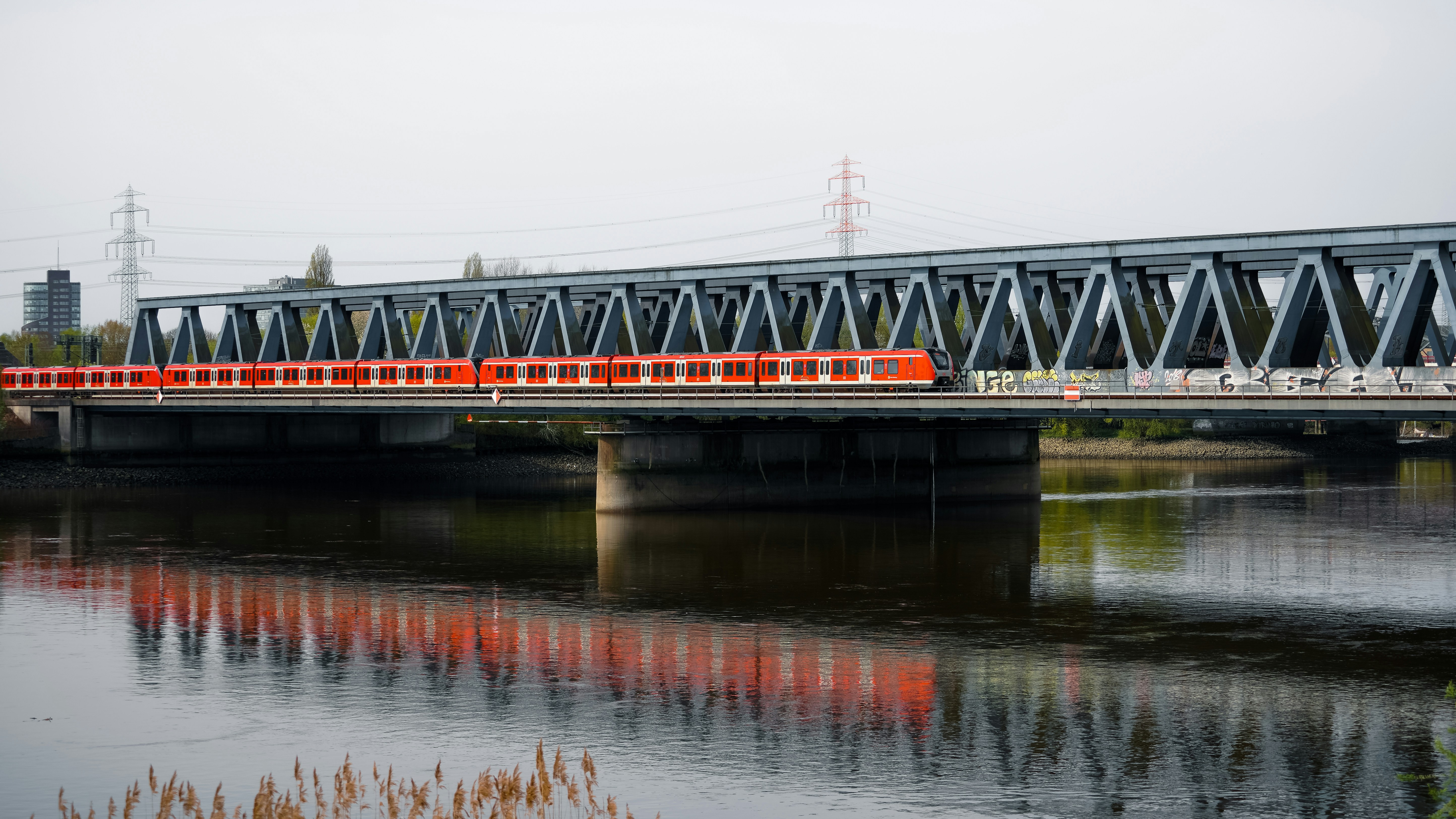 Red Train on a Steel Crescent: A Riverside Transit Slice