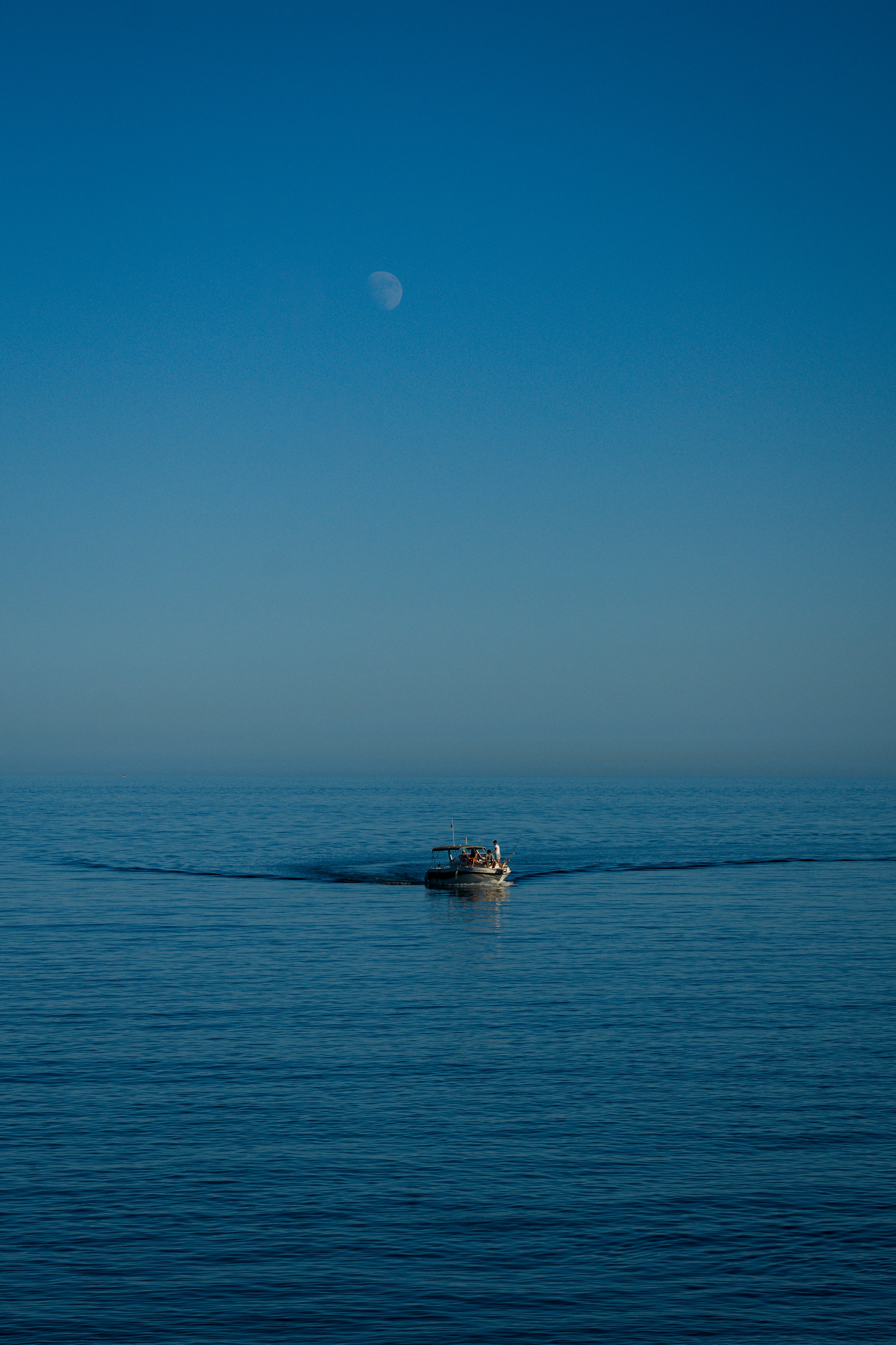 Moonlit Wake: A Small Vessel Traces a Quiet Path Across Calm Seas