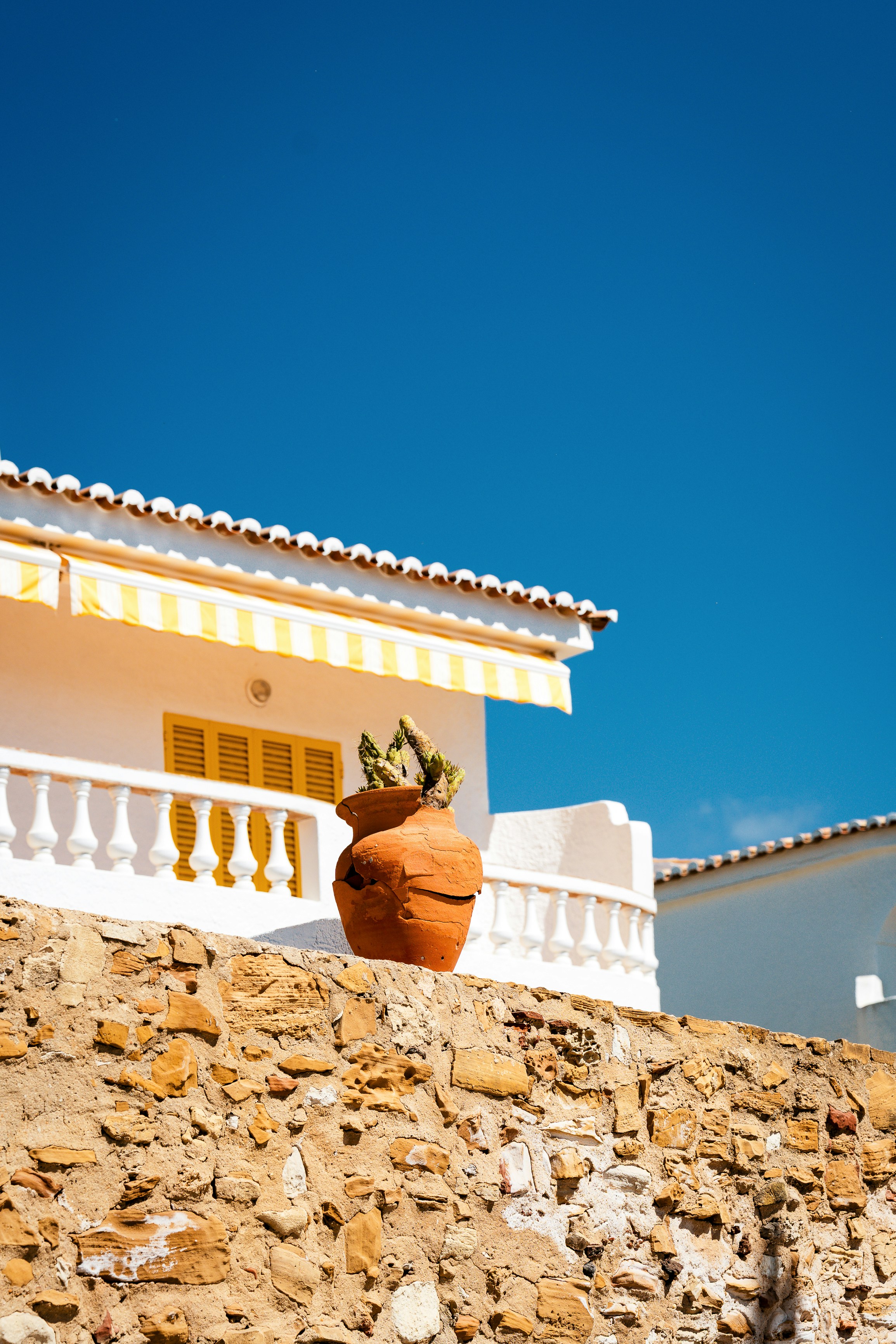 Terracotta Vessel on a Sunlit Terrace Against a Mediterranean Sky