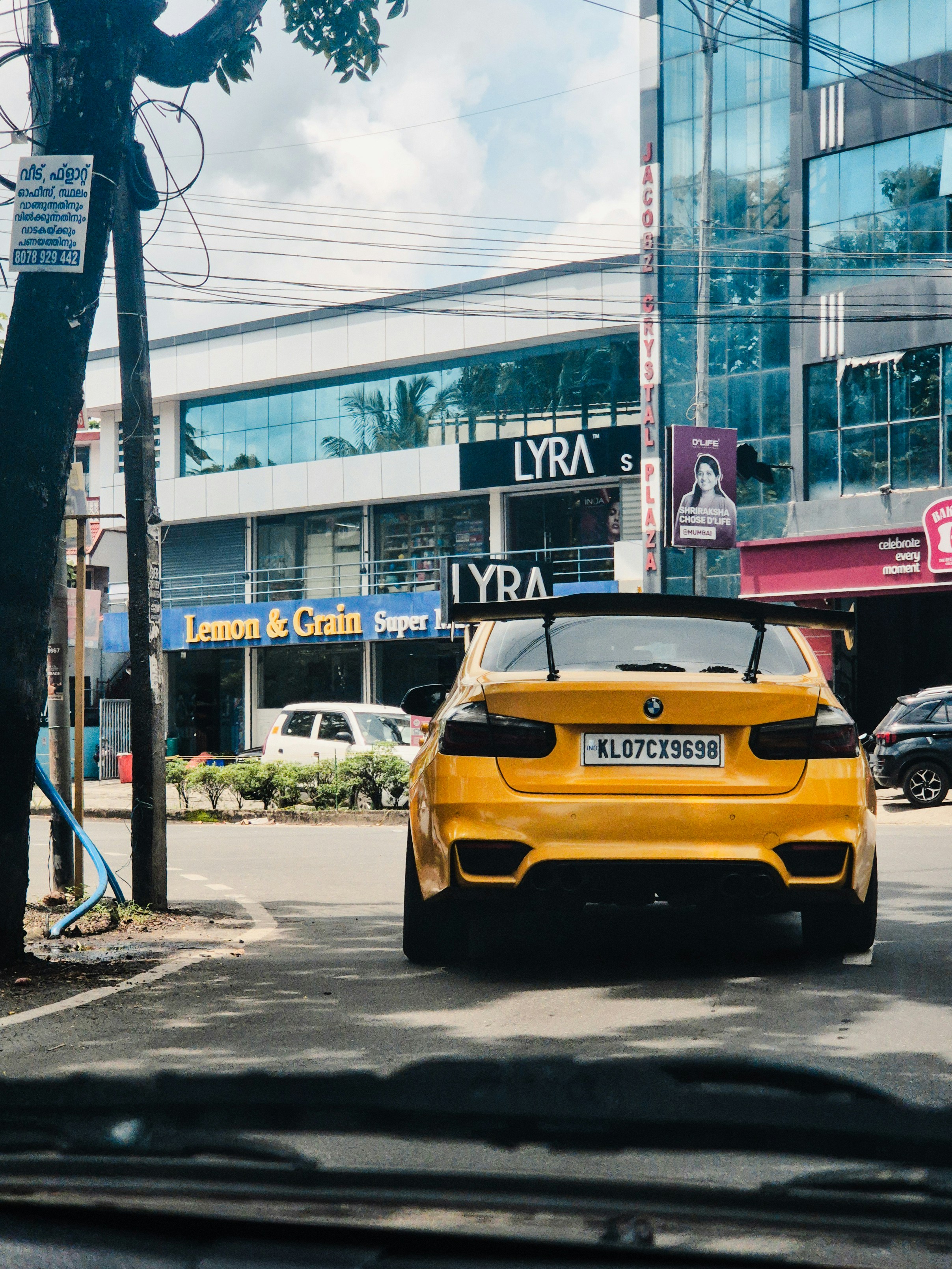 Yellow sedan at the urban junction with bold 'LYRA' signage