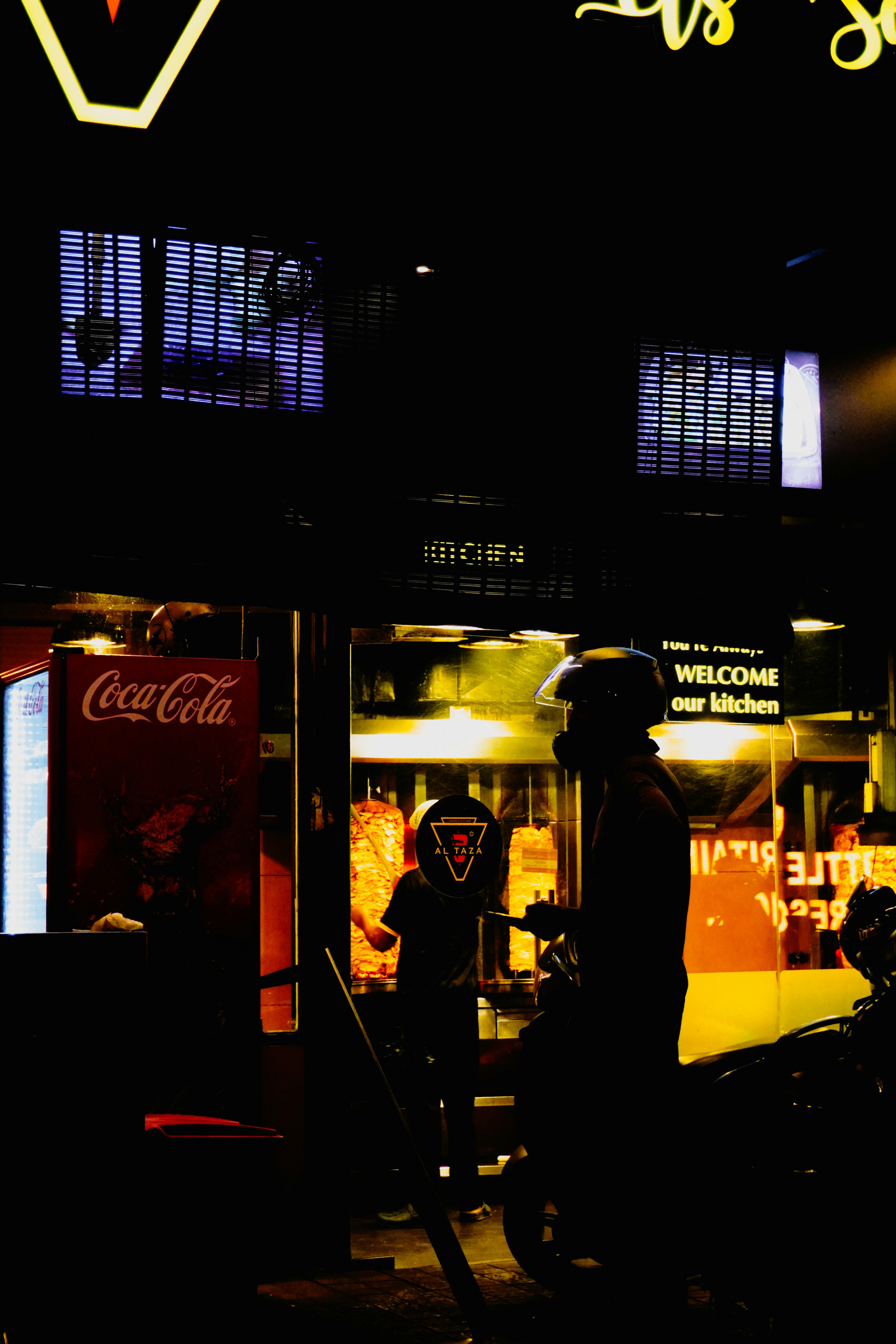 Neon silhouette: Night street food glow behind a lone rider