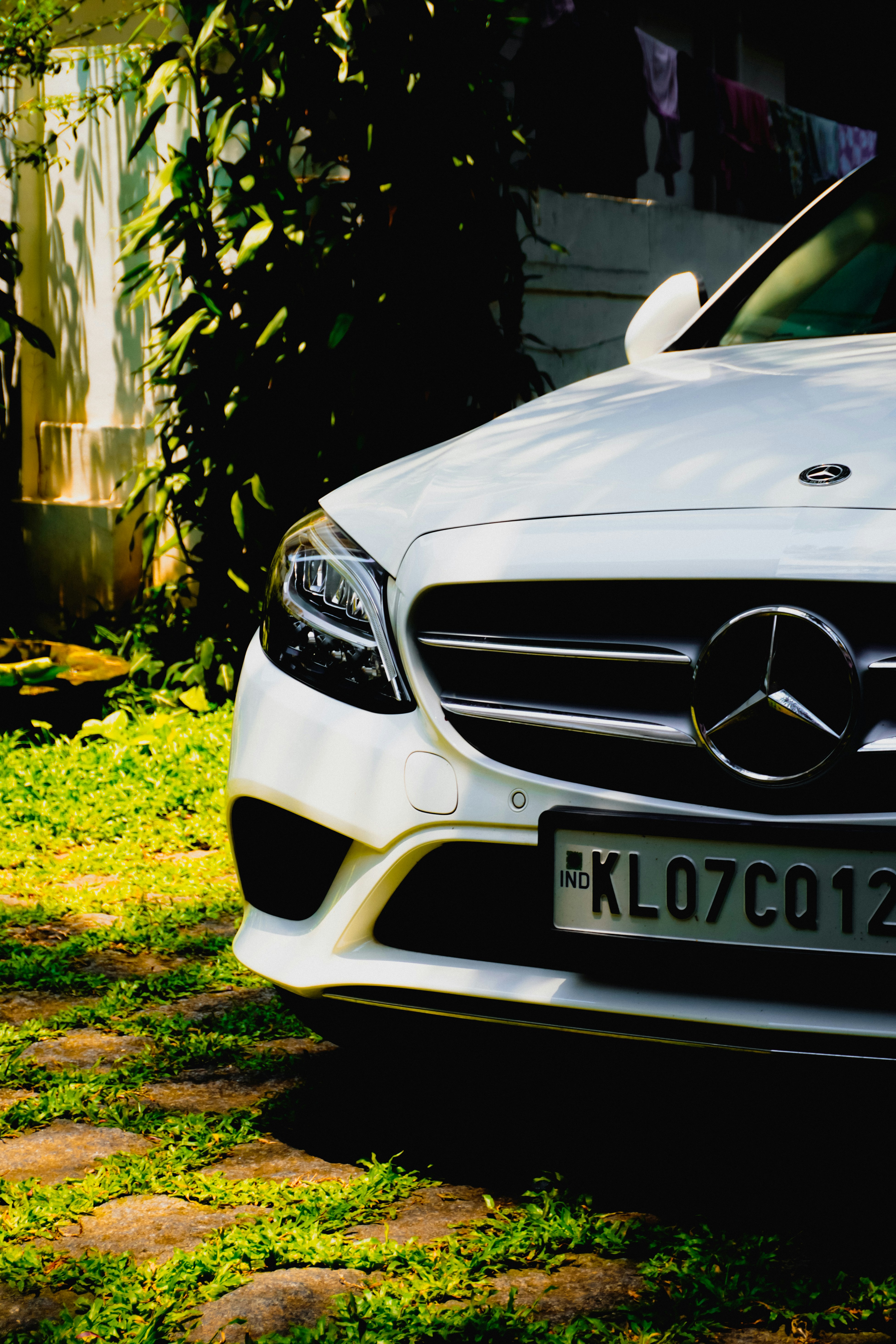 Front View of a White Mercedes Sedan in a Greenyard Driveway