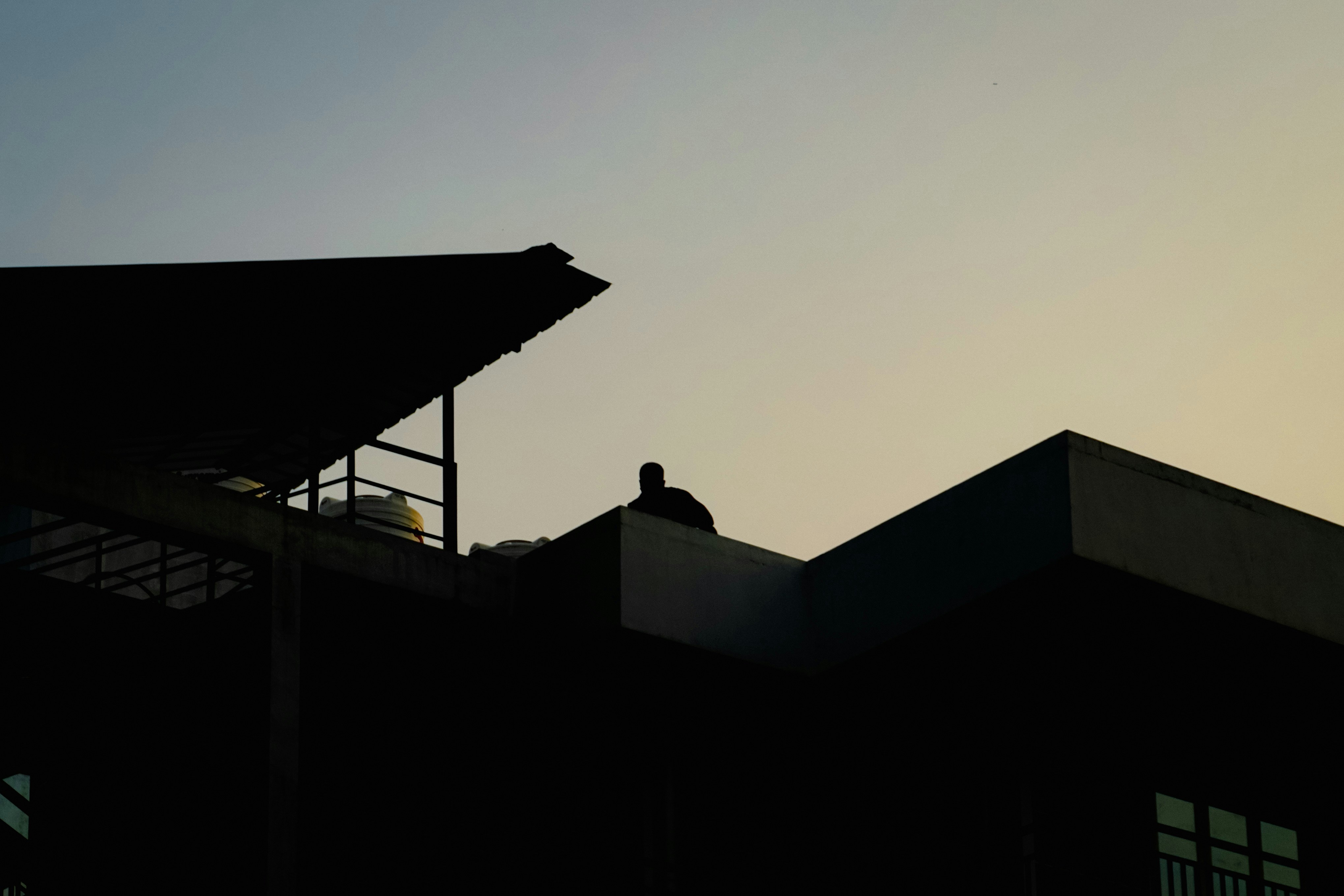 Silhouette on the Edge: A Rooftop Moment at Dusk