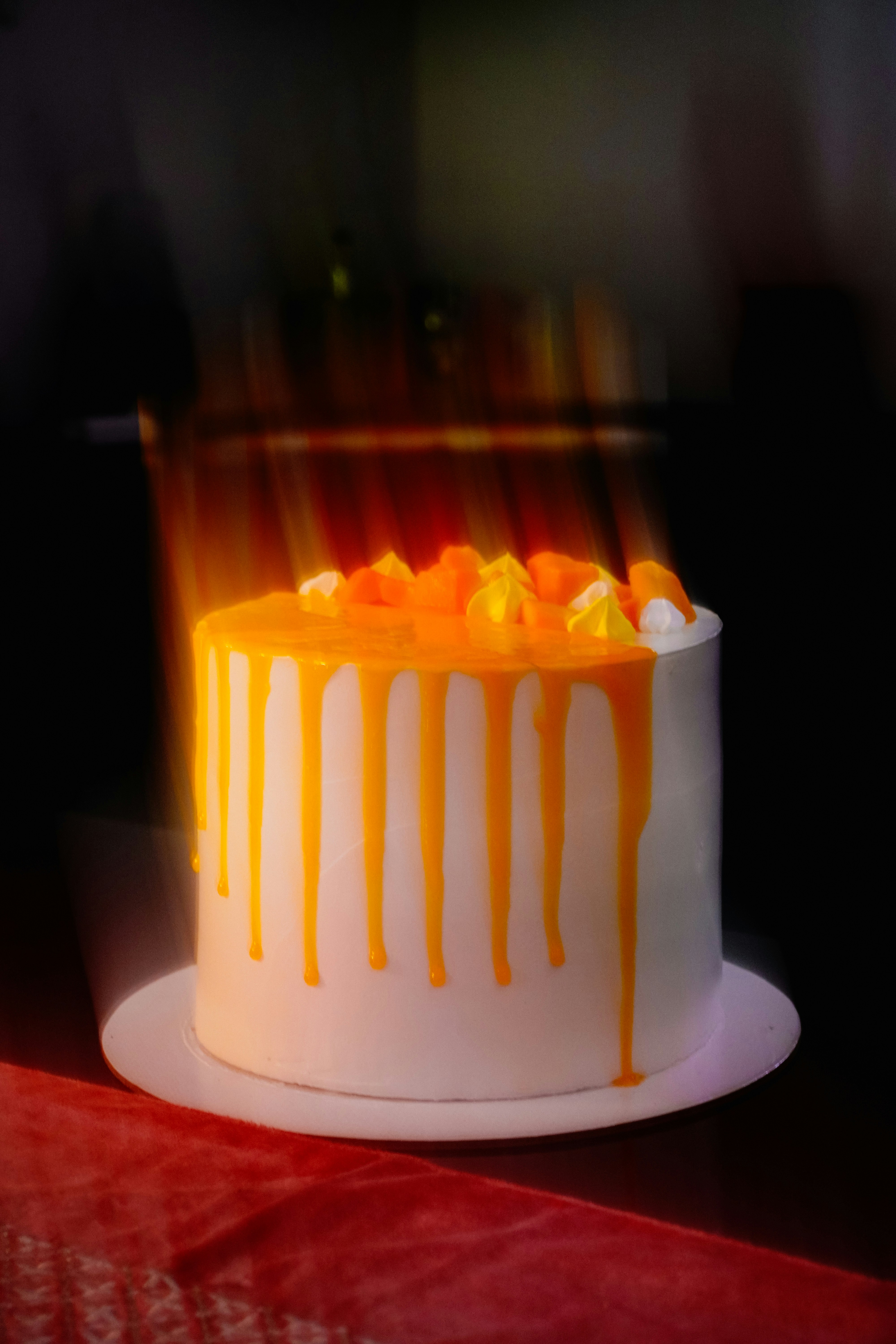 White cake with orange drip icing and bright glow.