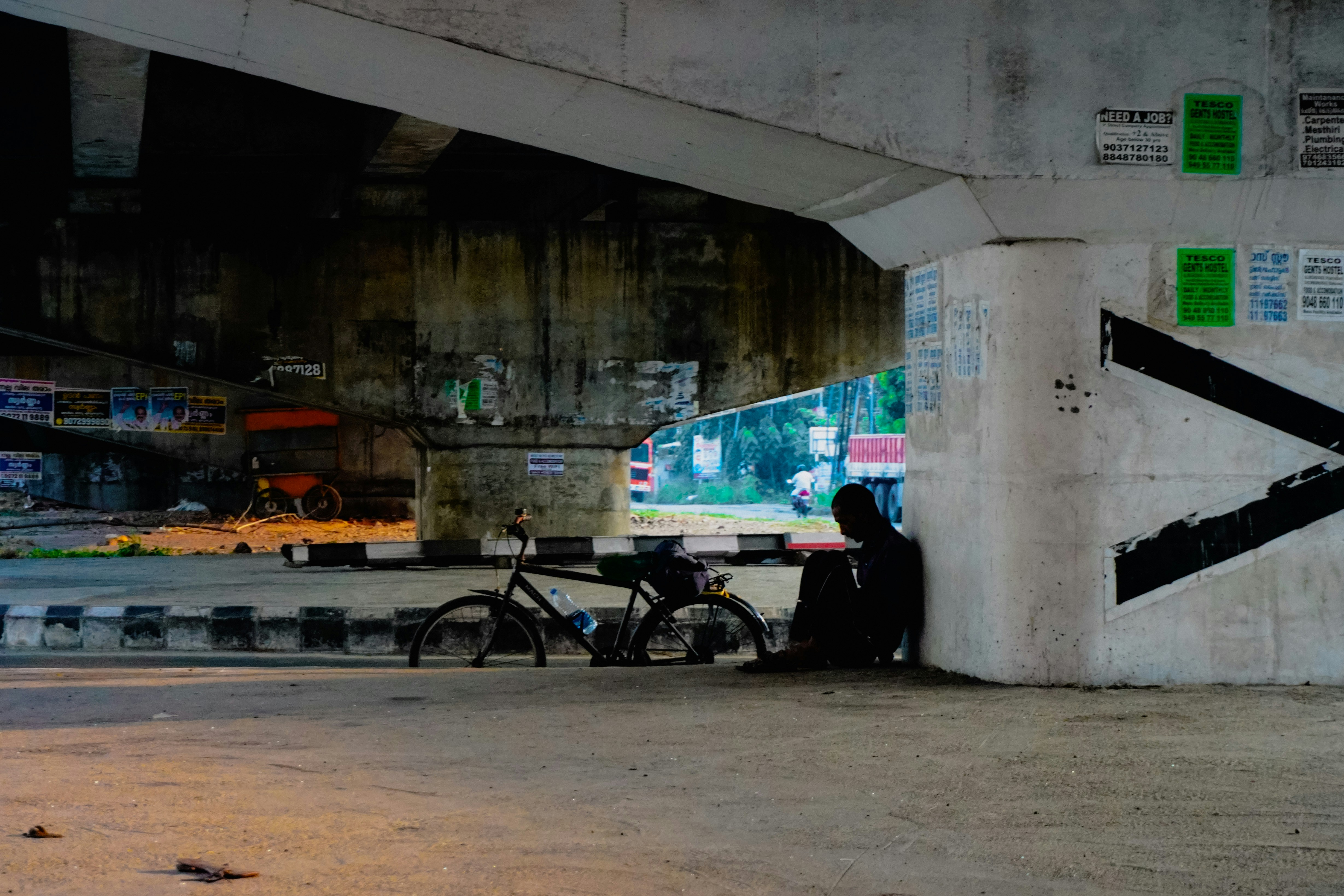 Underpass Refuge: Bicycle and silhouette in the shadowed arch