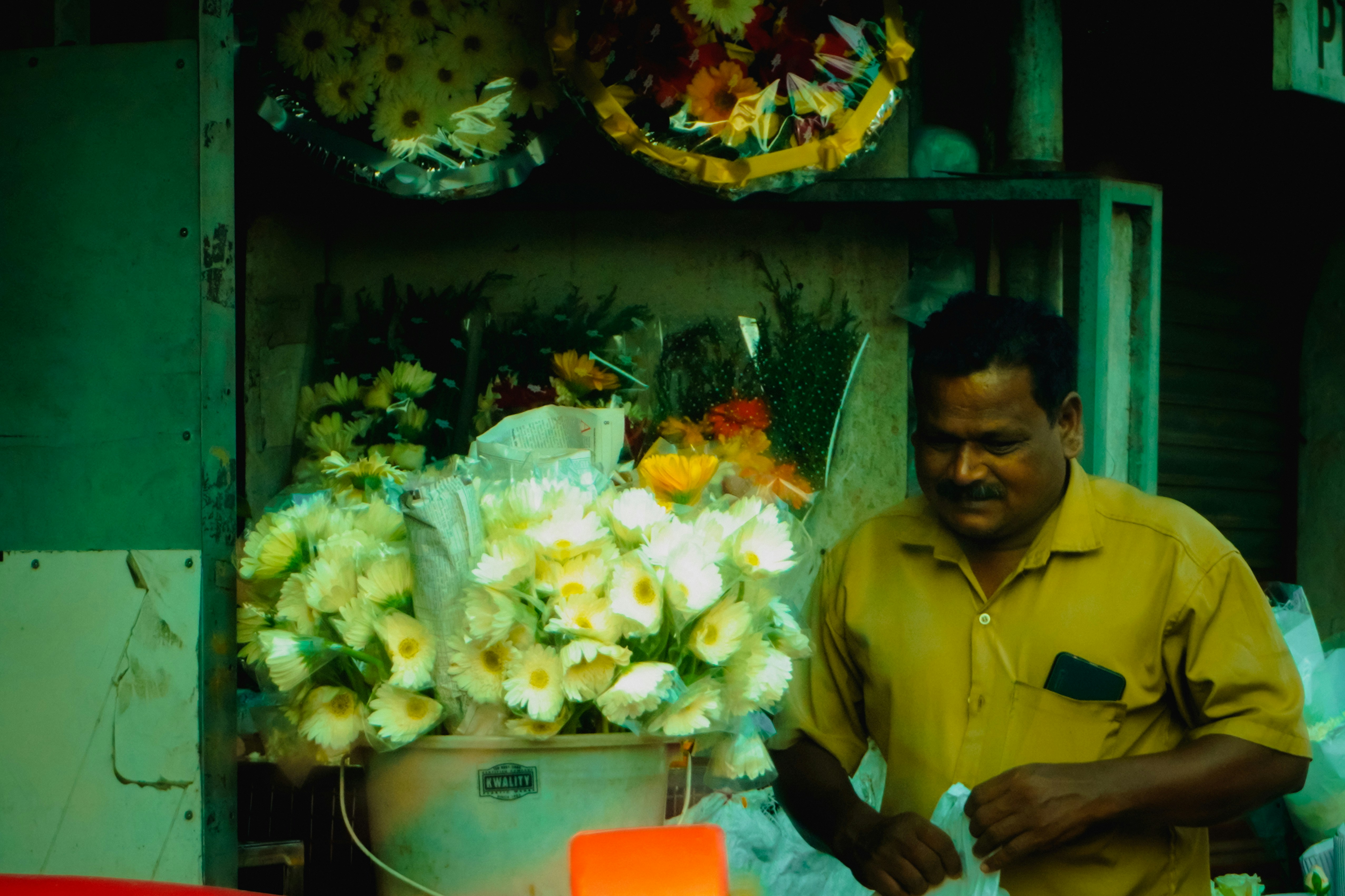 Market Vendor in Yellow Shirt Amid Fresh Floral Bales
