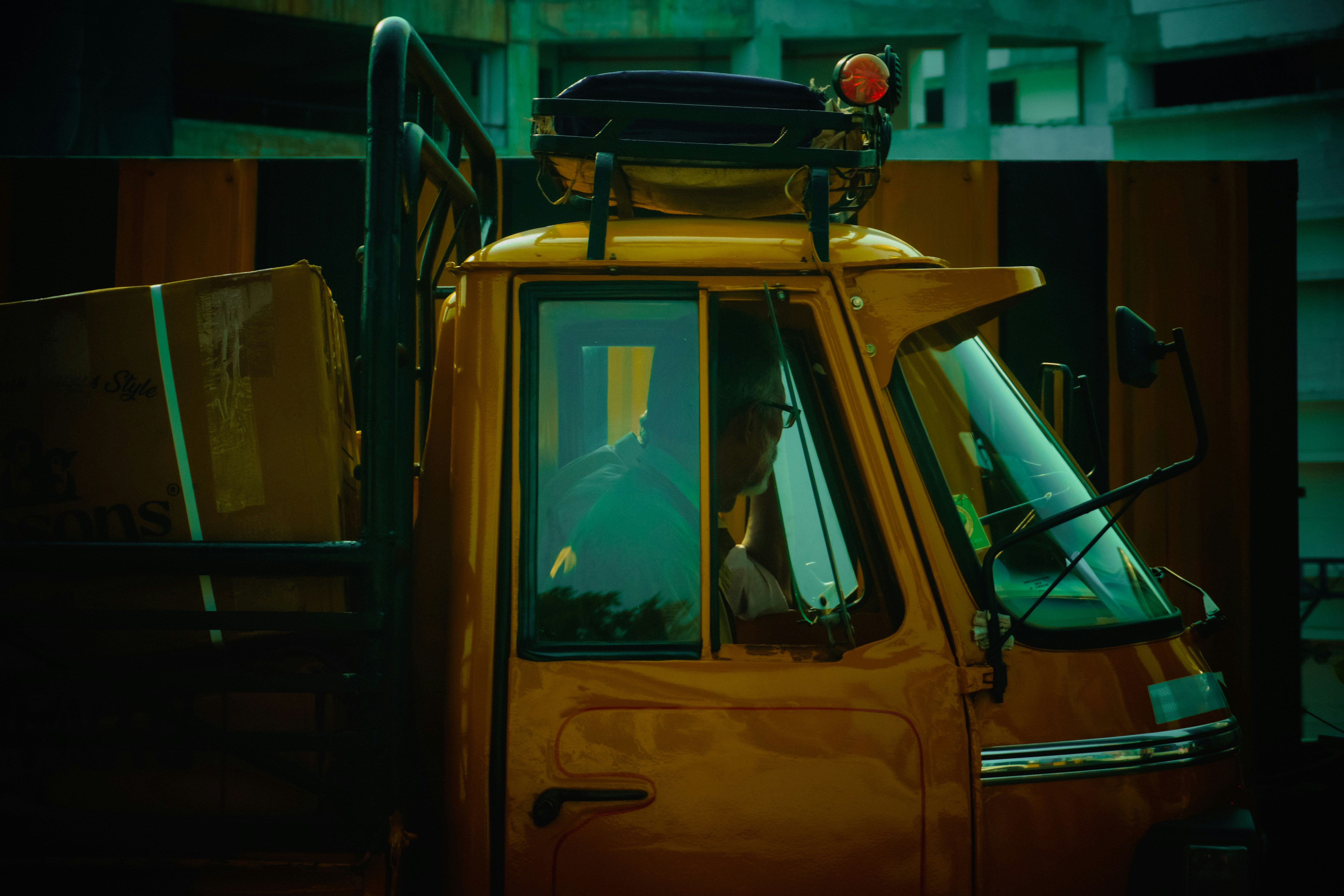 Three-wheeled orange truck carrying boxes.