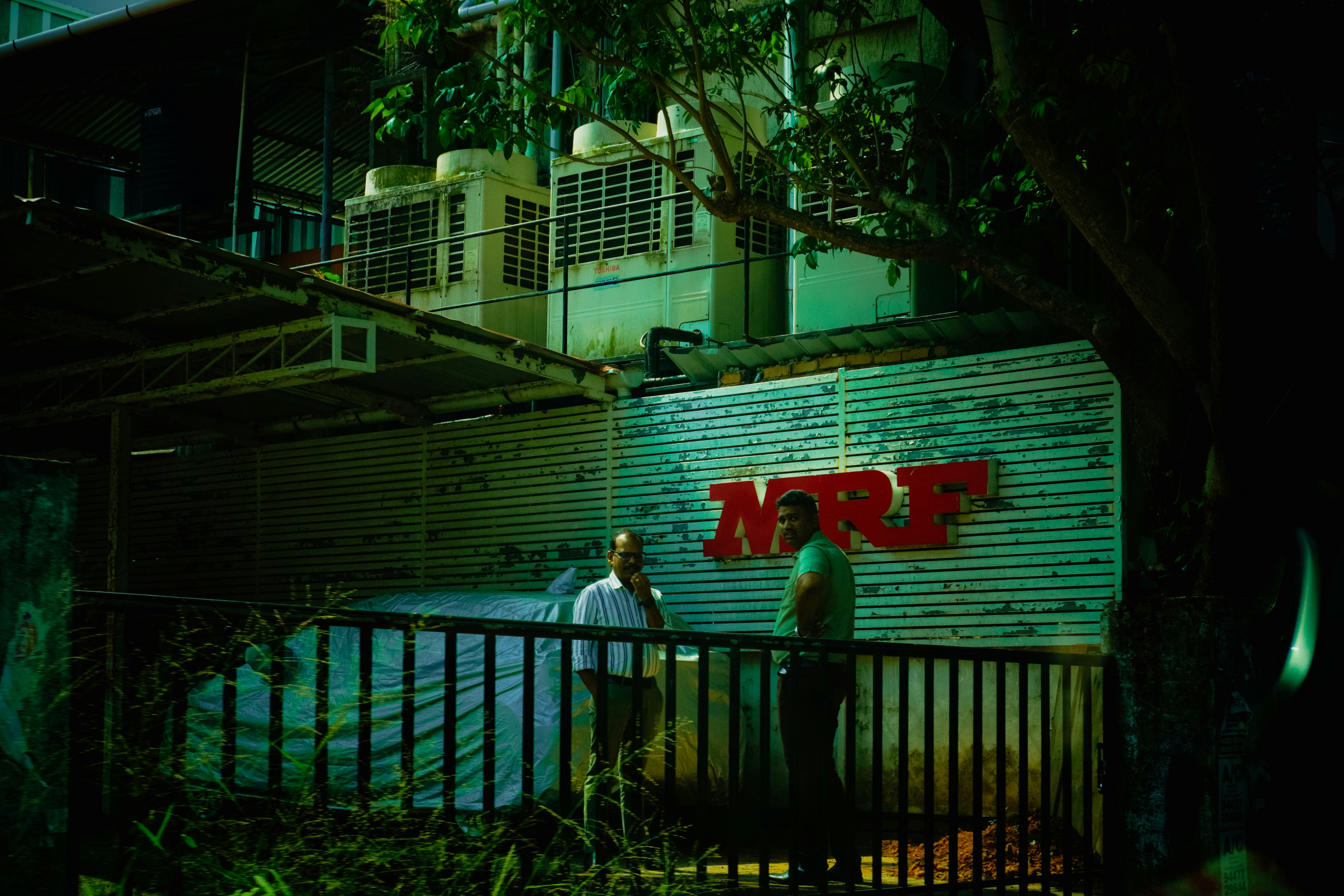 Men stand by mrf logo wall with rooftop ac units.