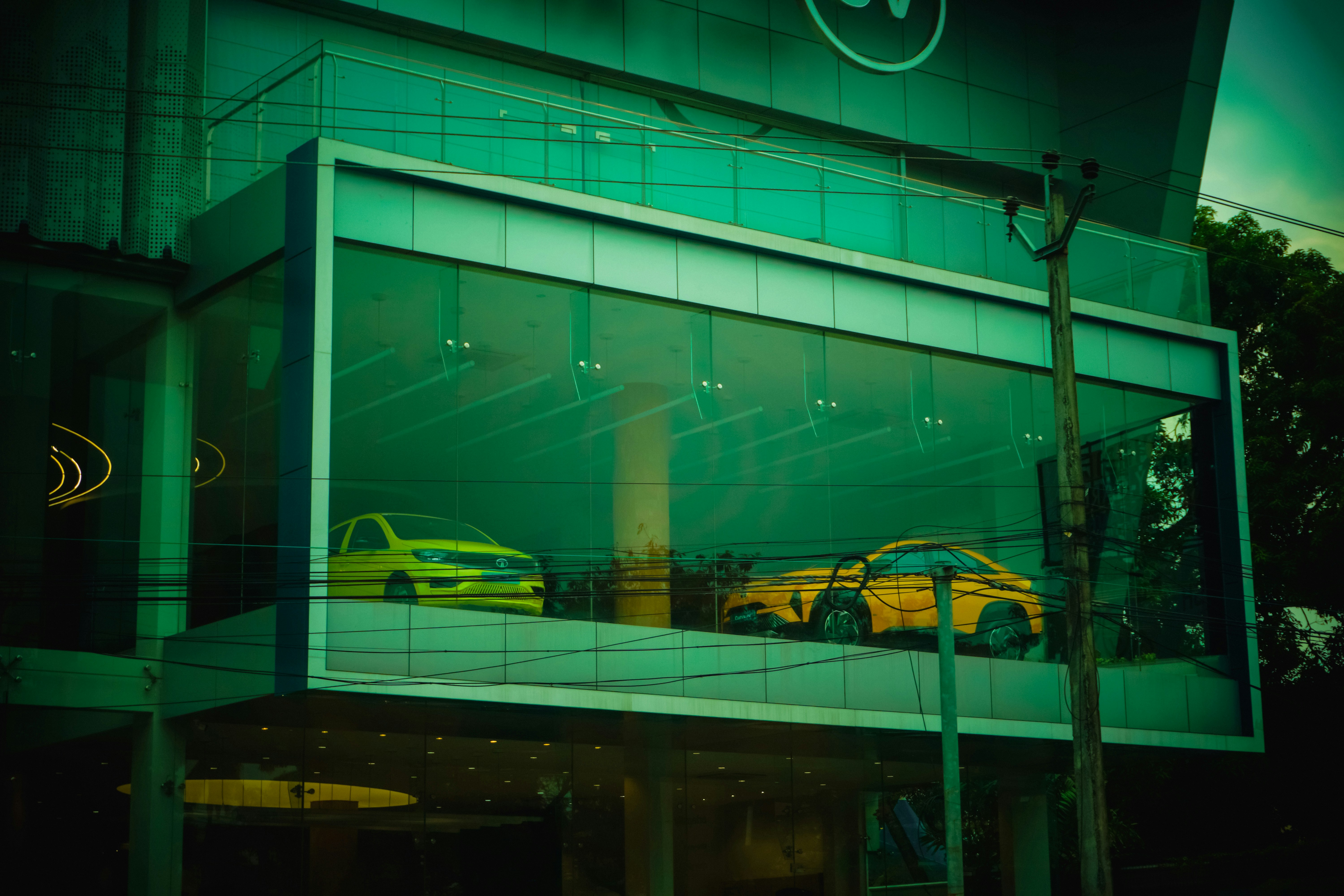 Yellow cars displayed in a building's large glass window.