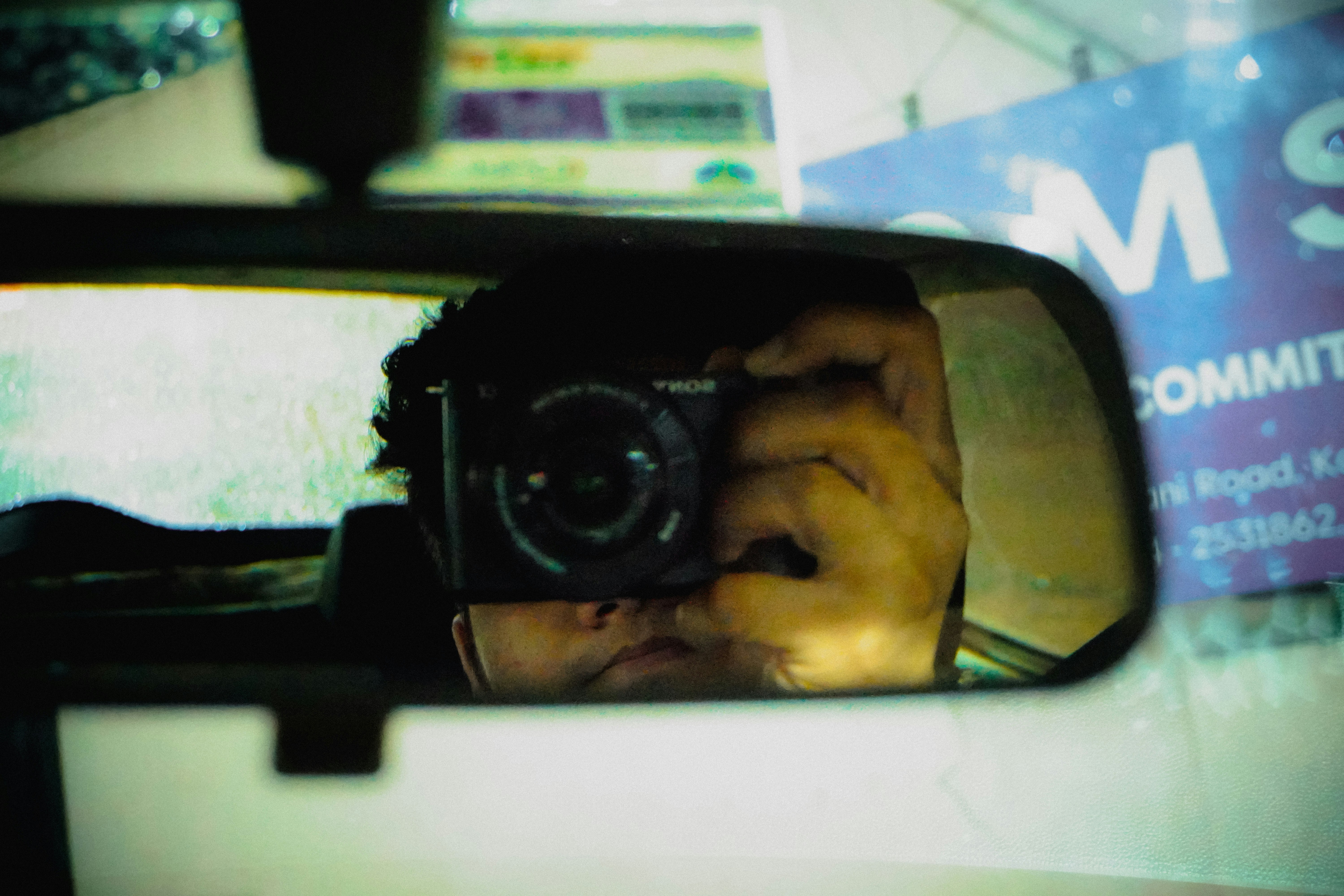 Person taking a selfie in a car's rearview mirror.