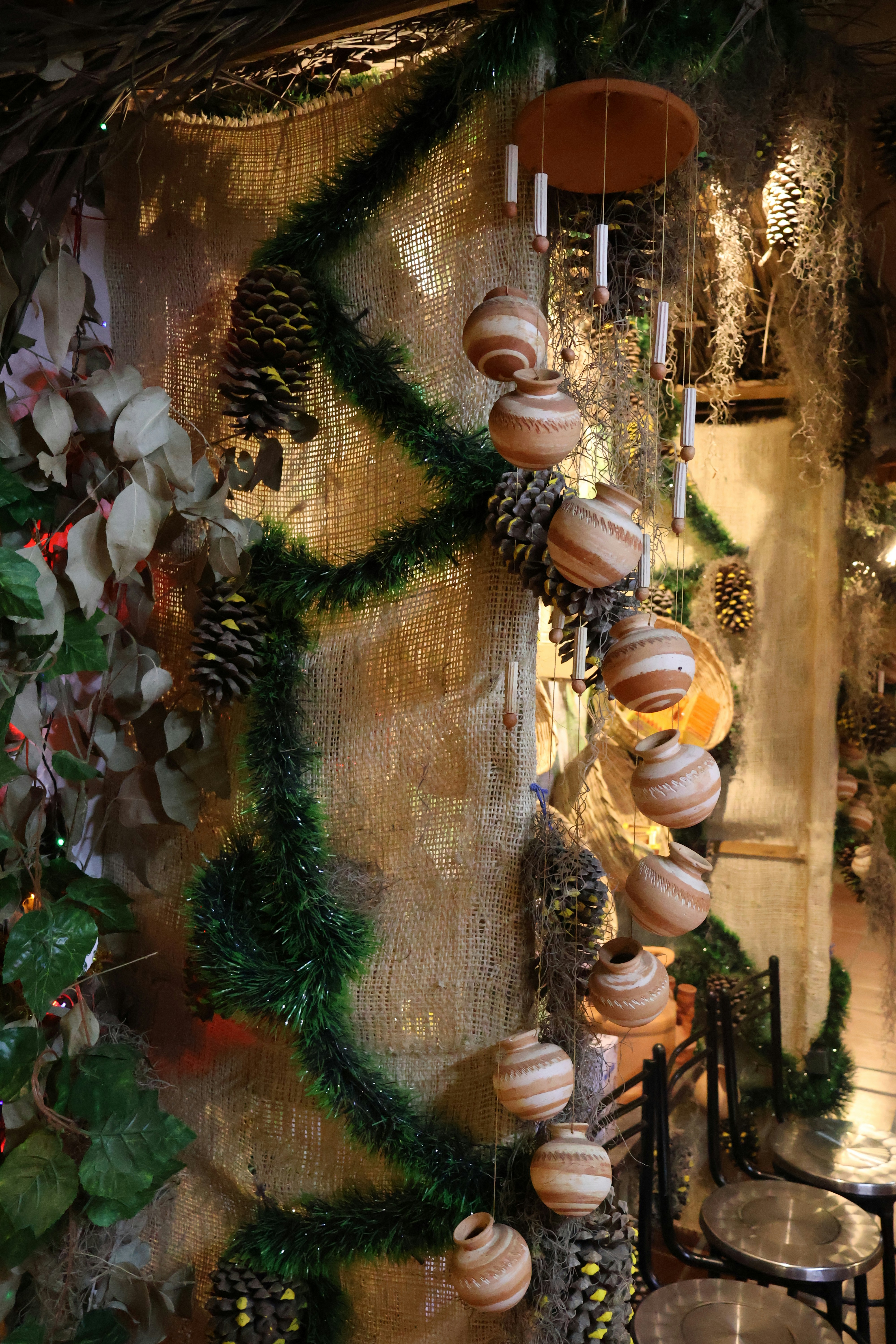 Decorative Holiday Orbs and Pinecones Dangling Along a Burlap Wire Wall