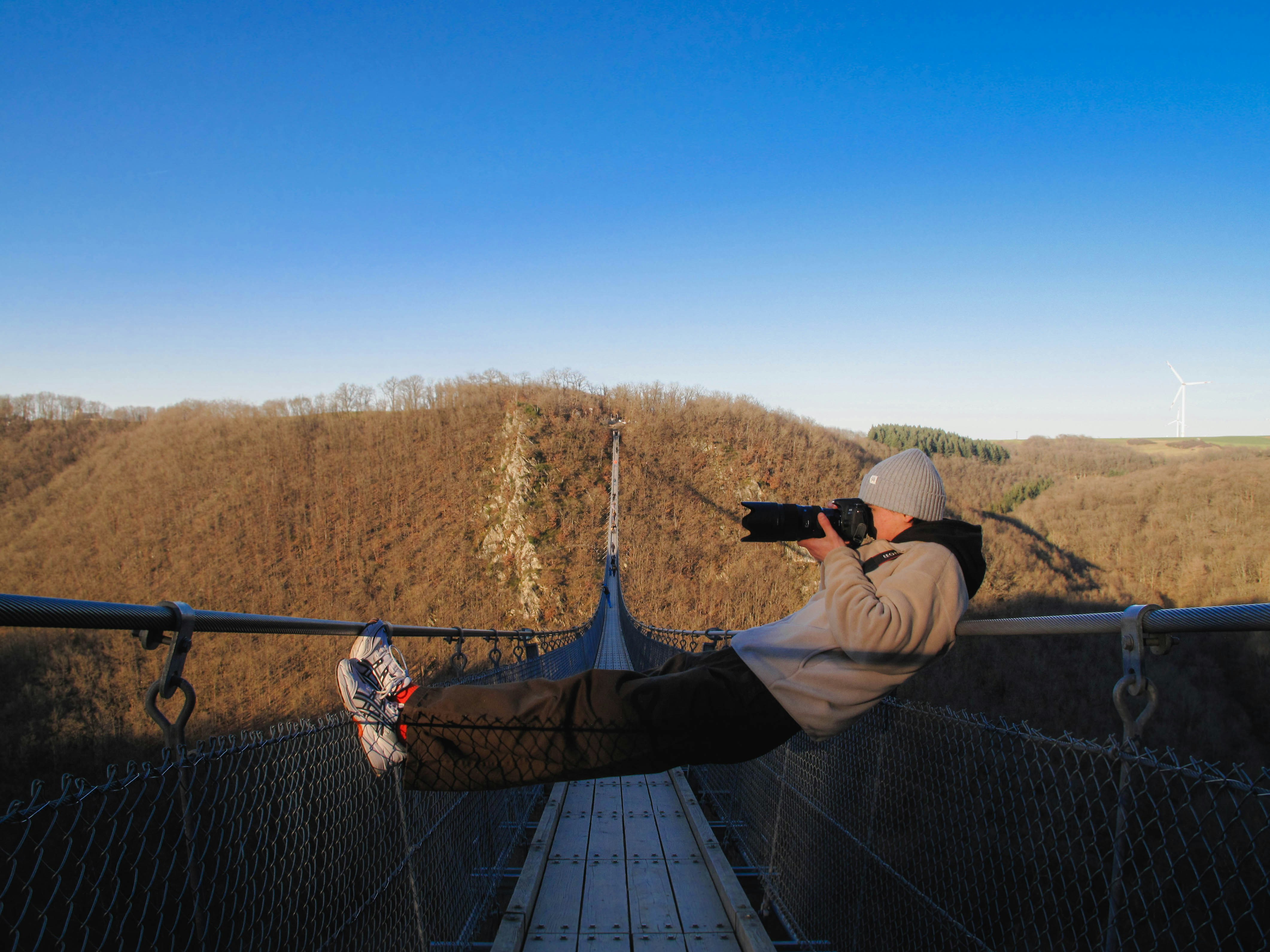 A photographer perched mid-suspense on a high suspension bridge