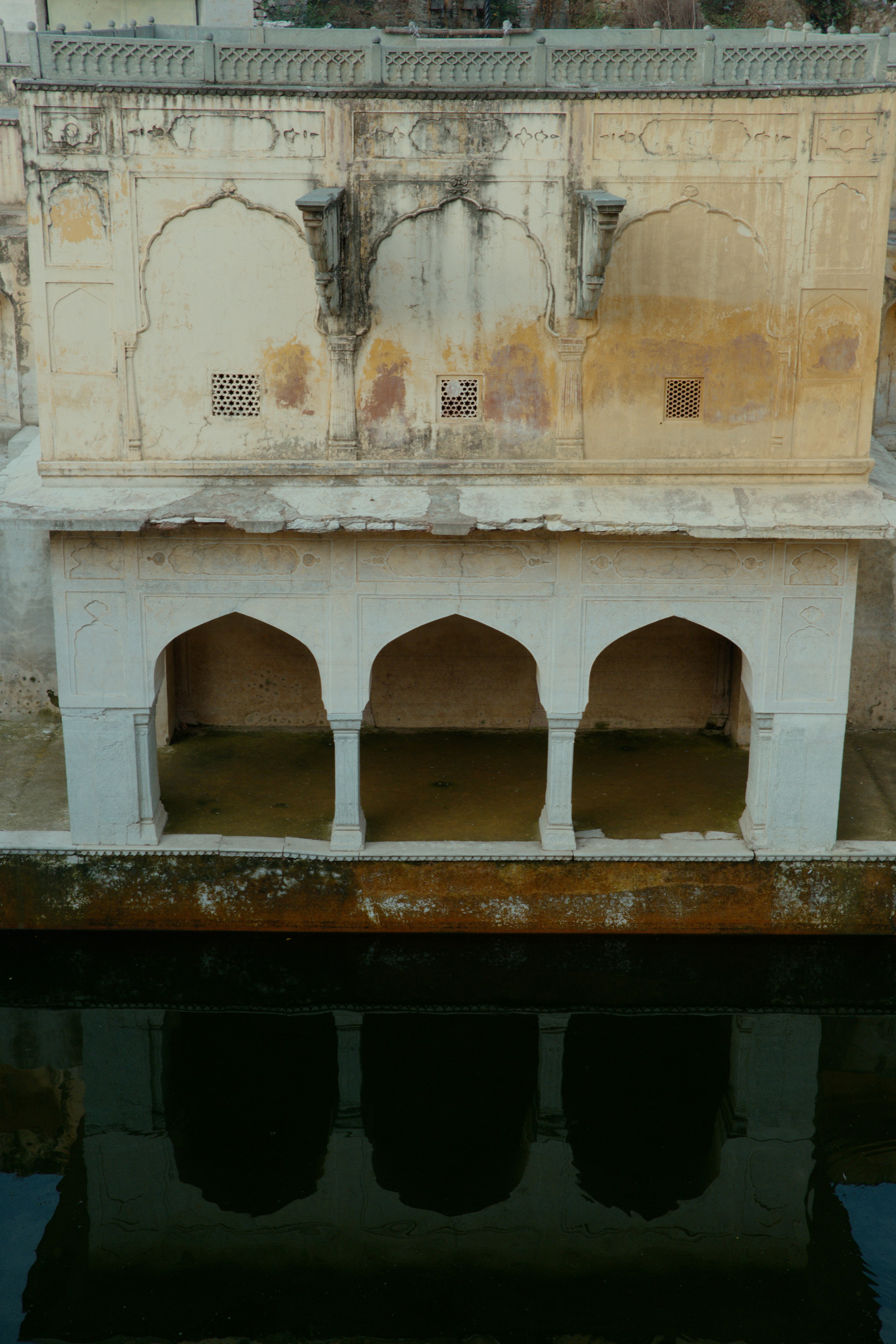 Refined arches and weathered facade: a calm reflection beside a sunlit canal