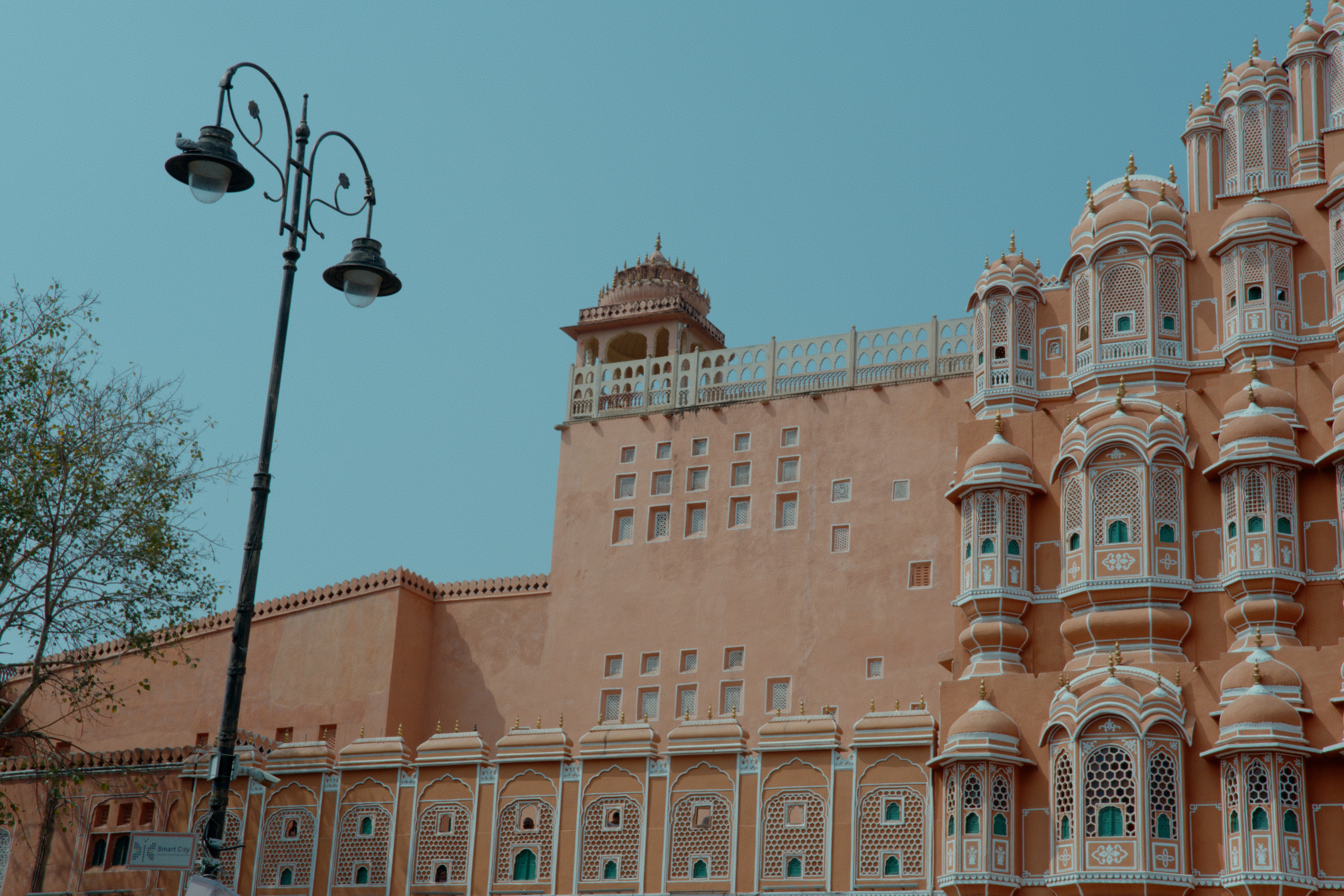 A pink palace with ornate windows and a street lamp.