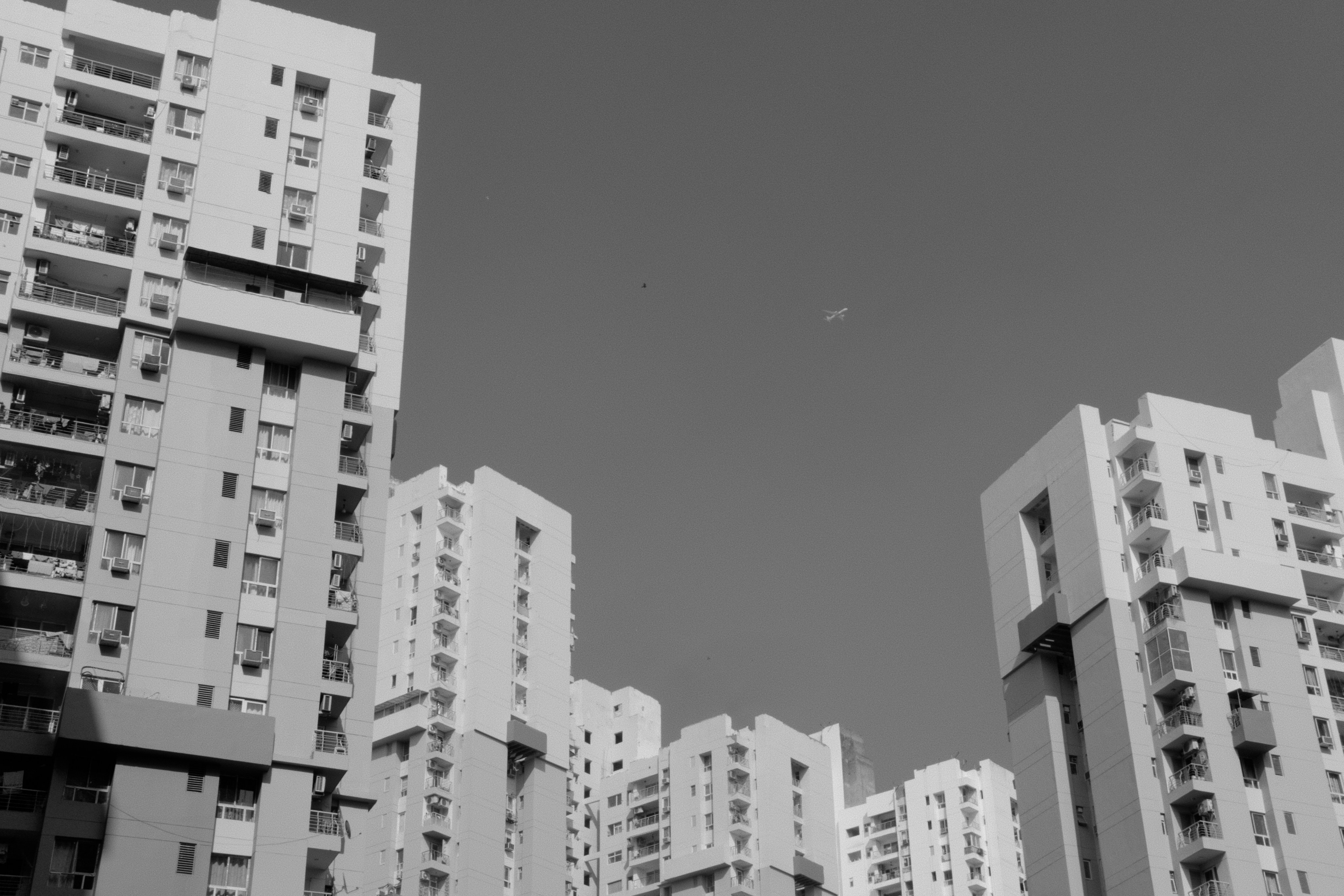 Tall apartment buildings and a distant airplane in the sky.
