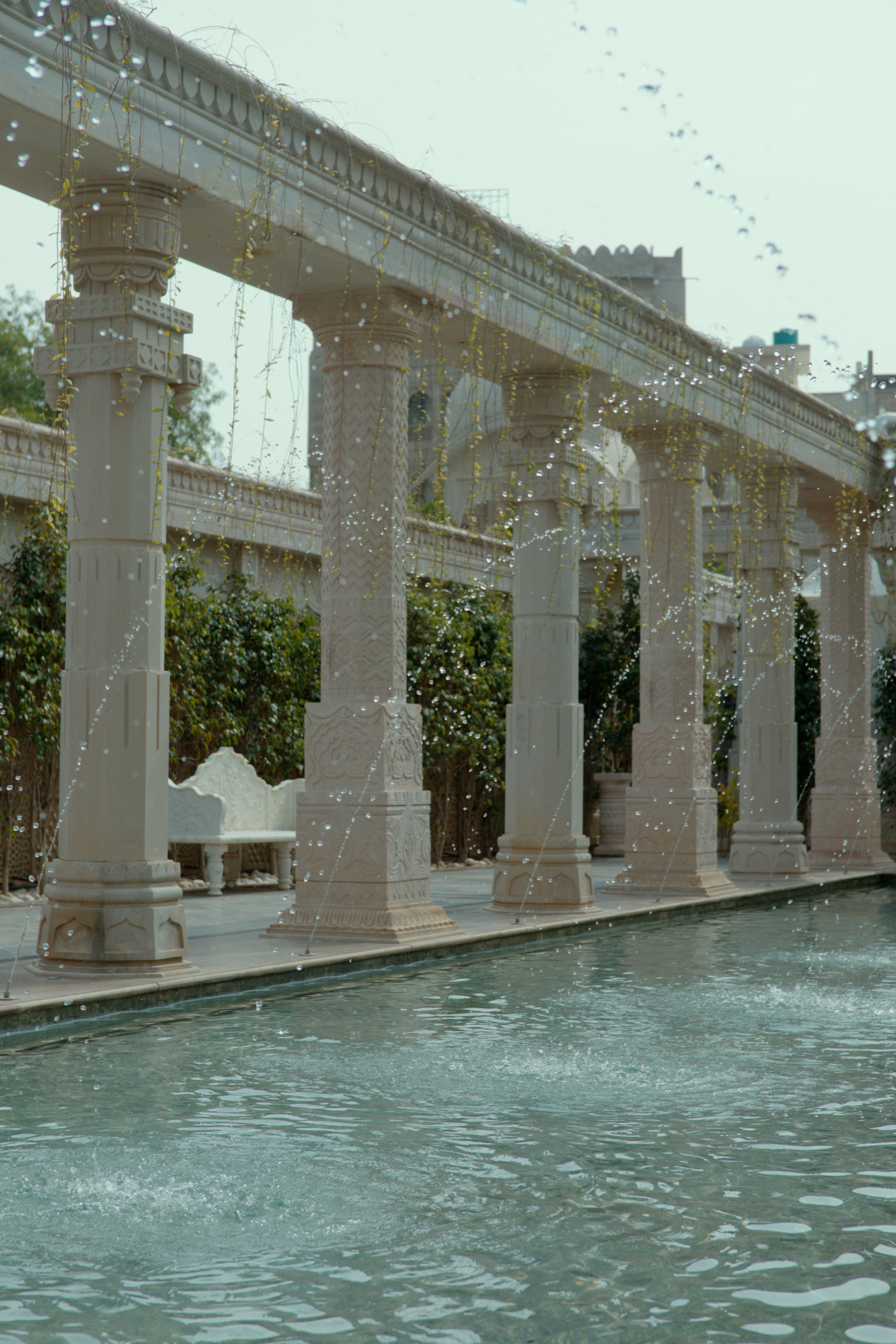 Stone Colonnade Over Water: Rows of Pillars Framing a Dappled Fountain