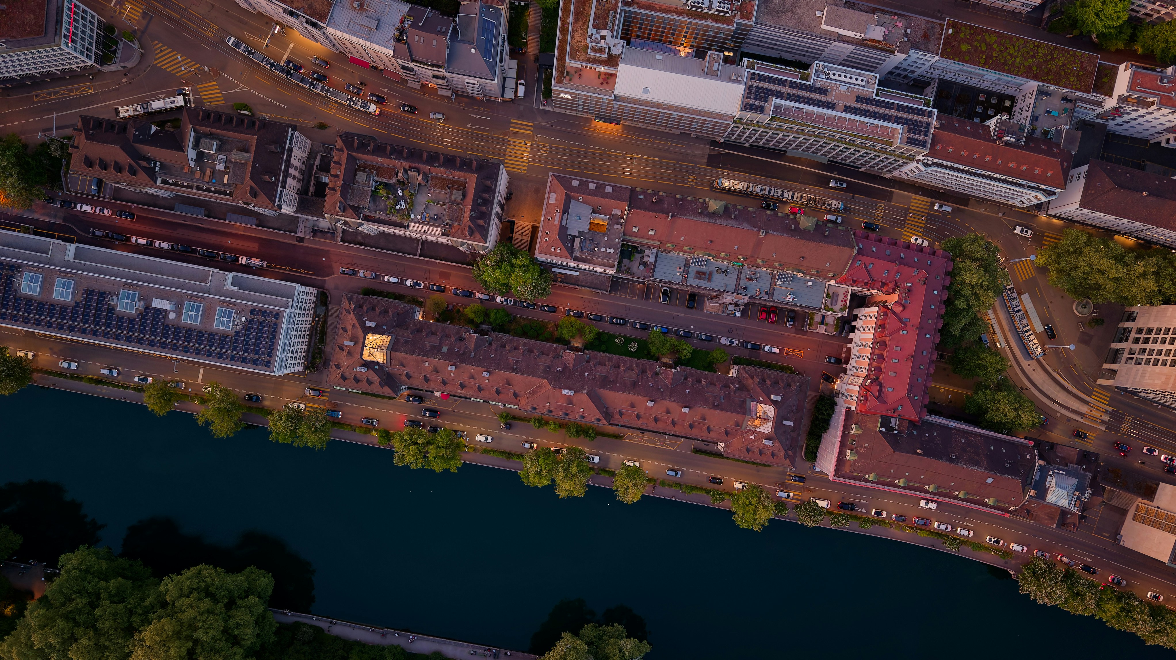 Aerial city view with buildings and river at dusk.