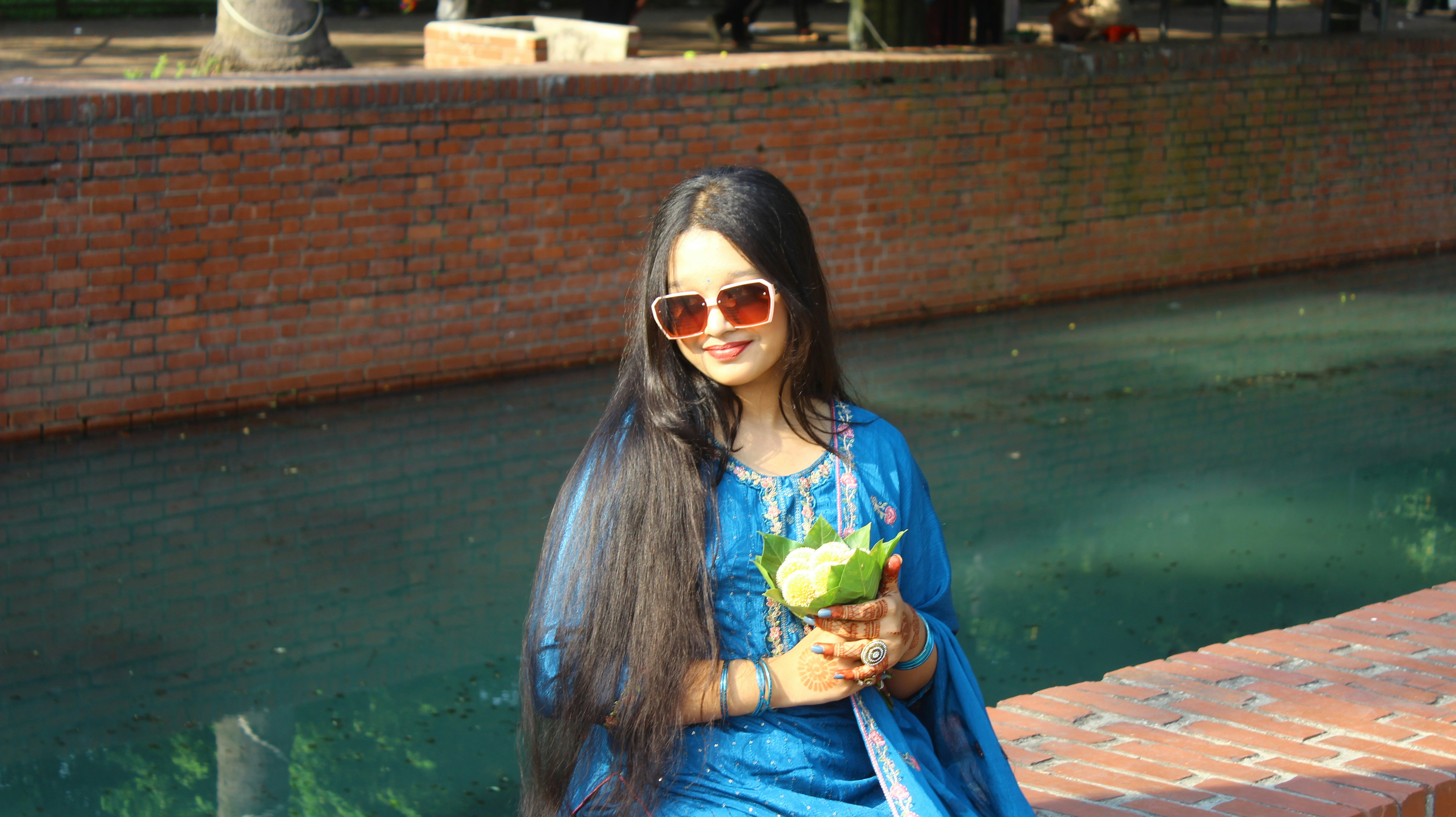 Sunlit Serenity: A Youthful Portrait with Green Treats by the Canal